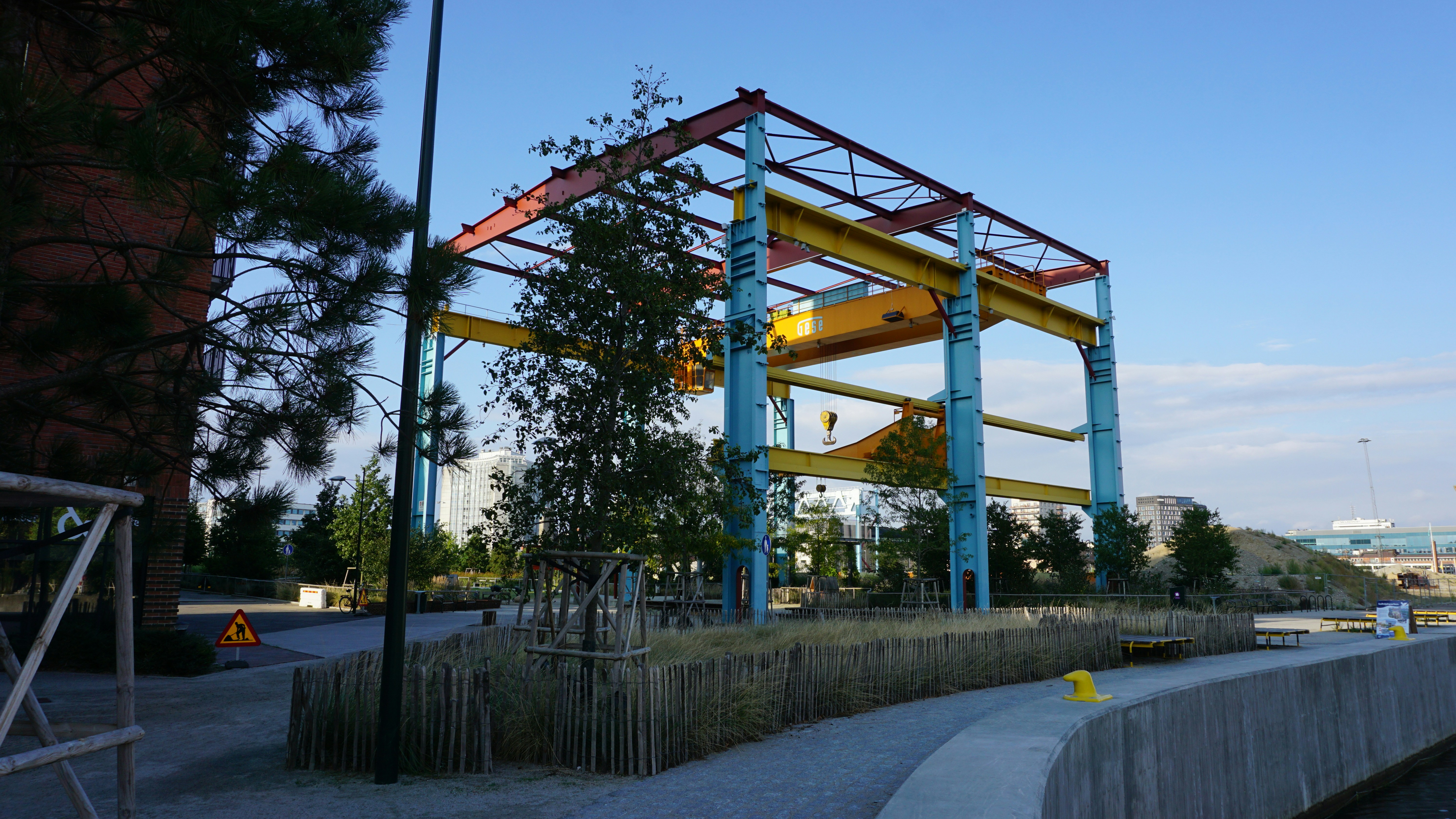 Colorful industrial frame rising above a calm riverside promenade
