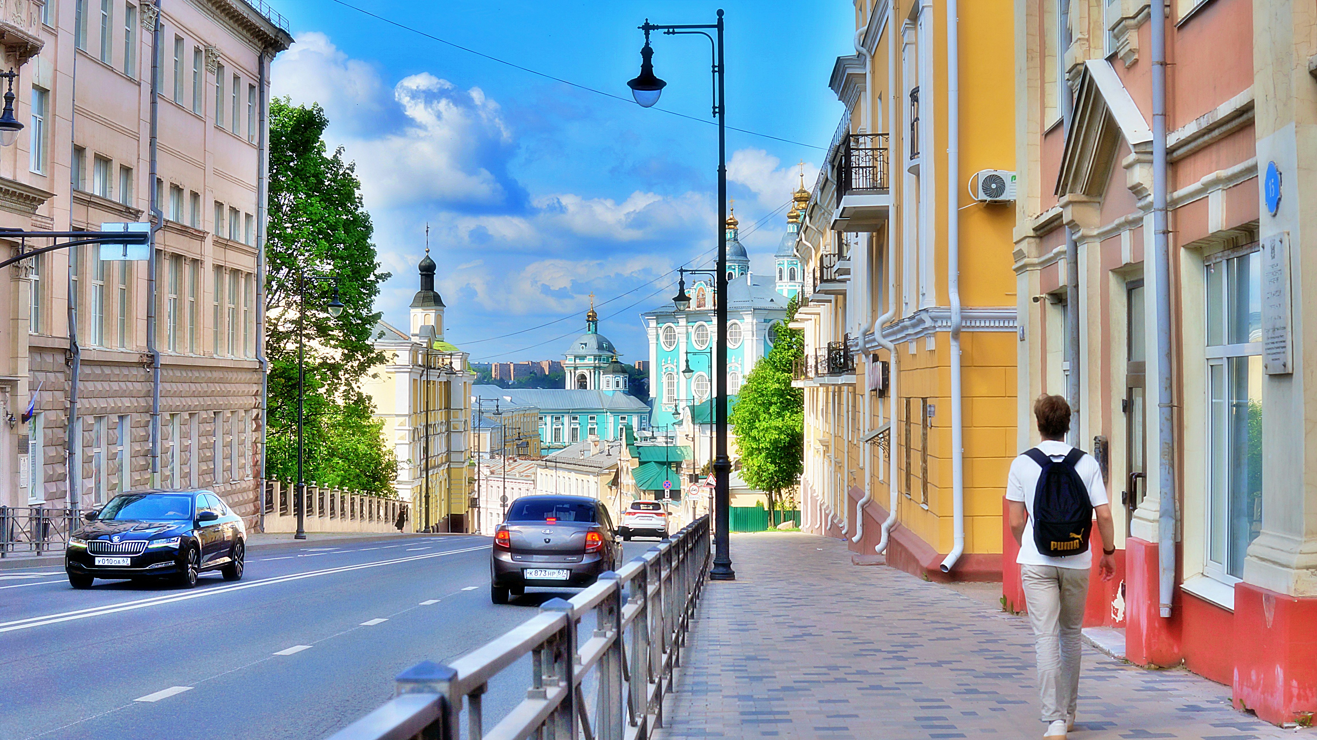 Sunlit Boulevard: A Pedestrian Wanders Between Colorful Facades