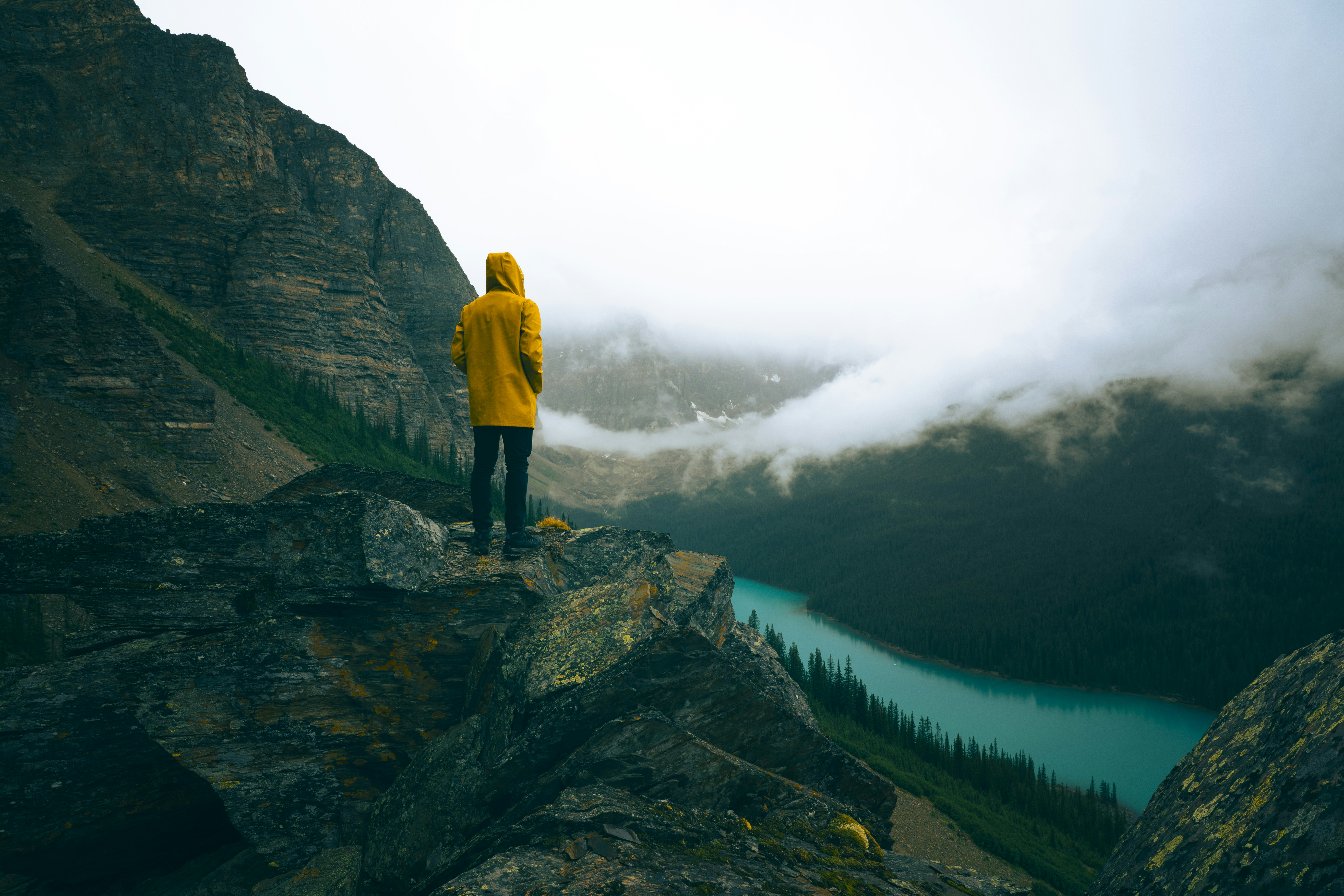 Yellow-clad silhouette on a jagged cliff above emerald fjord