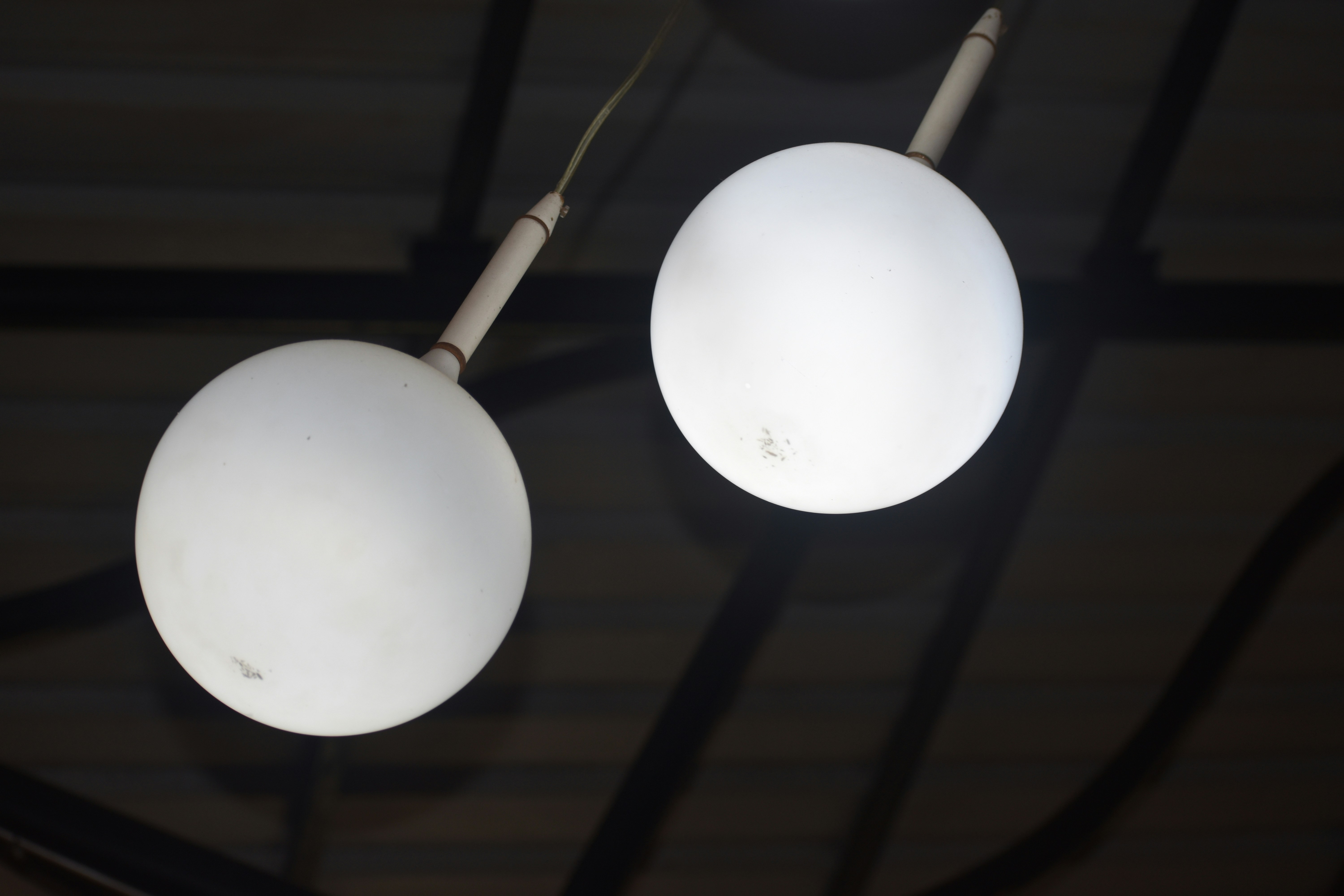 Two spherical light fixtures hang in a dark, industrial setting, their soft glow contrasting with the shadowed background.