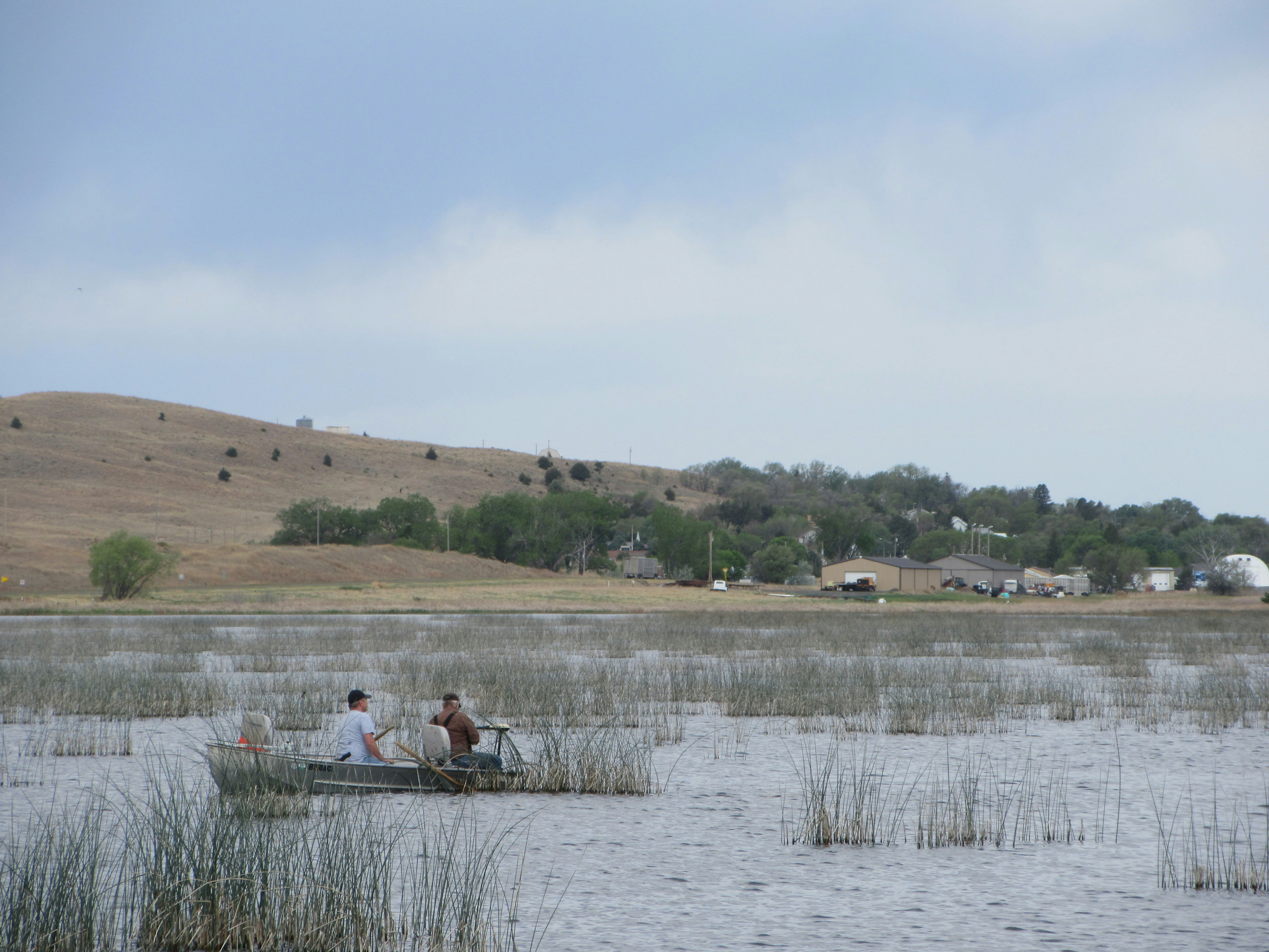 Two Anglers in a Calm Wetland Frame a Quiet Horizon