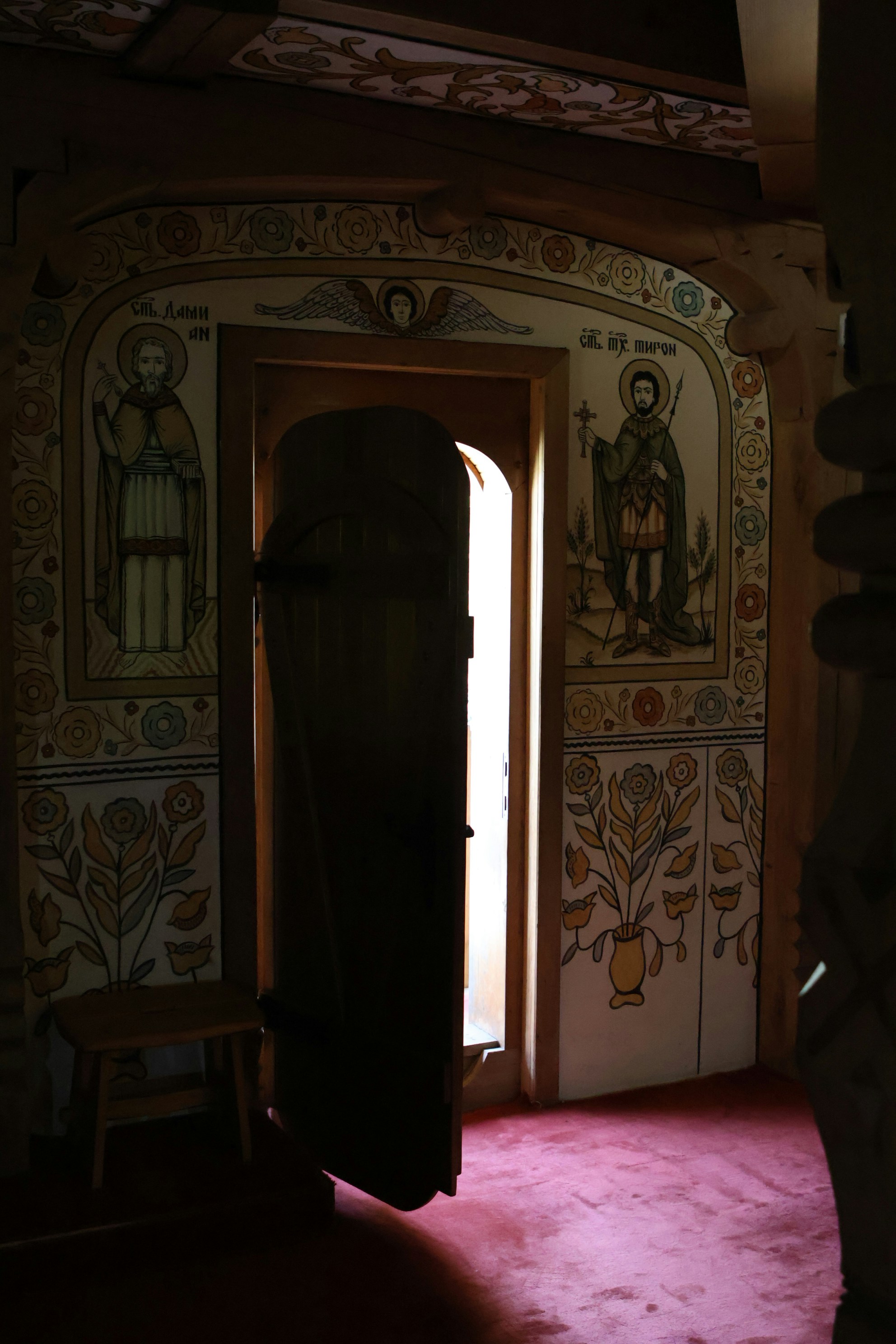 Doorway to Light: A Dim Church Interior with Painted Panels