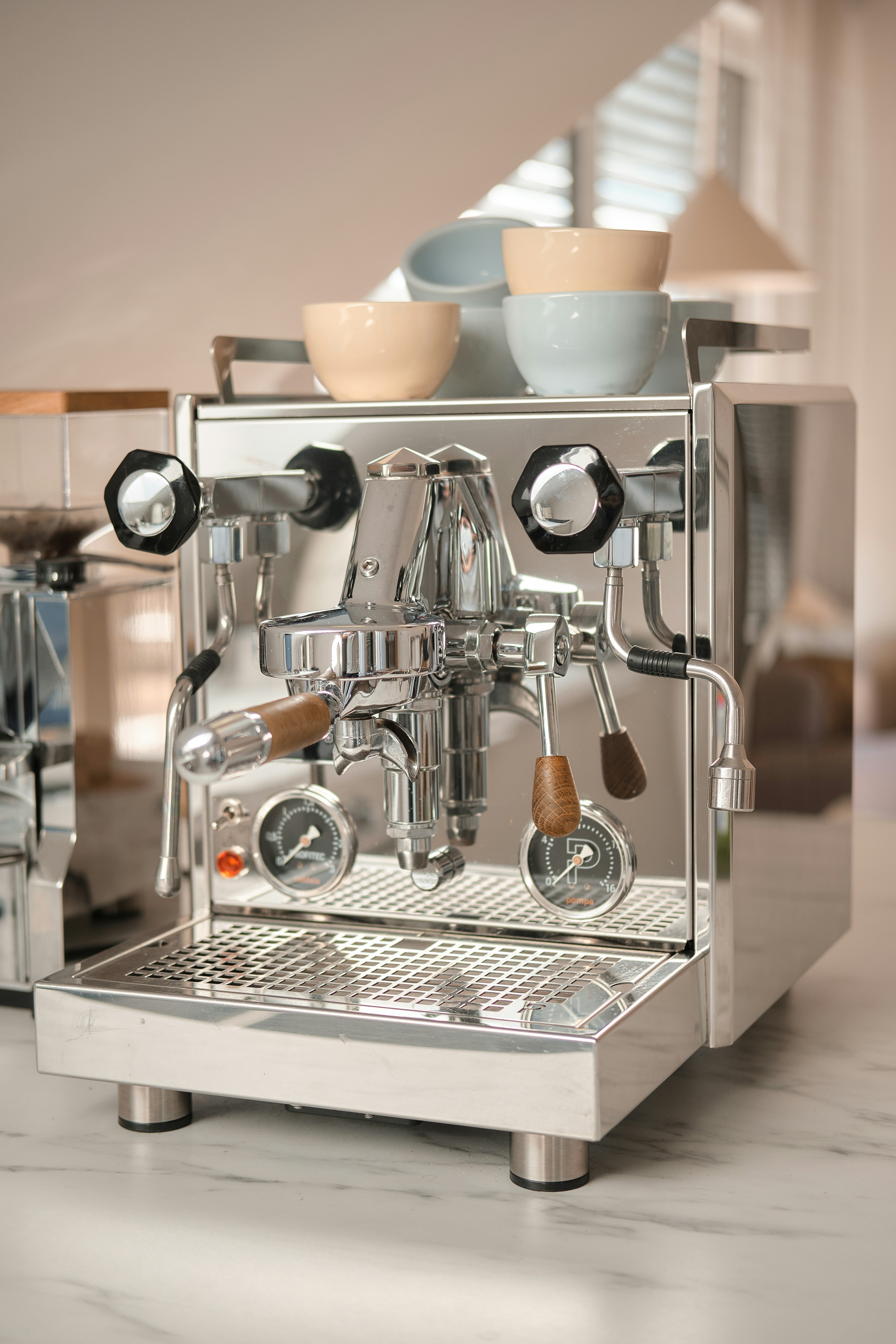 Twin-Portafilter Precision: A gleaming espresso machine anchors the counter with stacked cups above