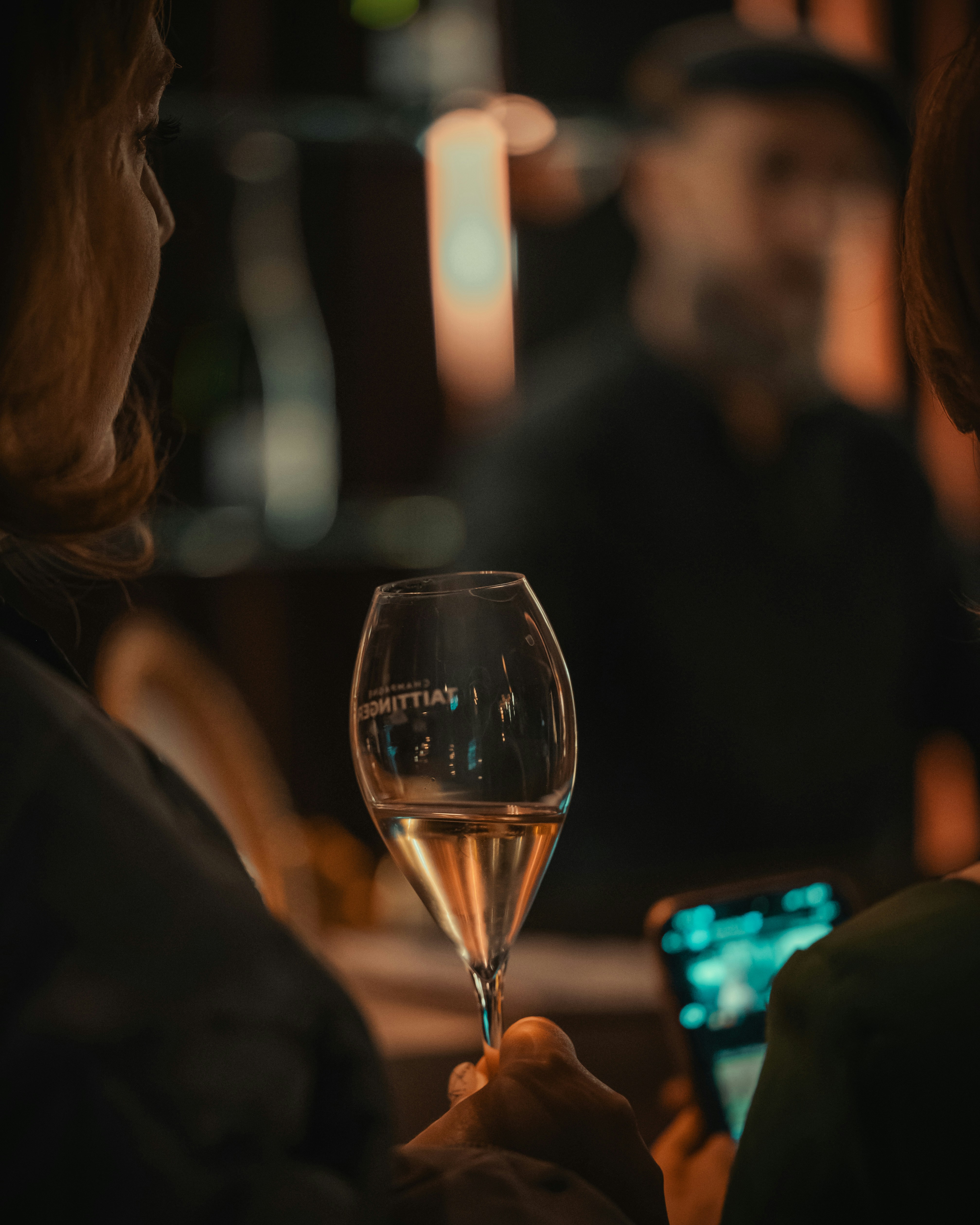 A person holding a glass of champagne in a dimly lit bar
