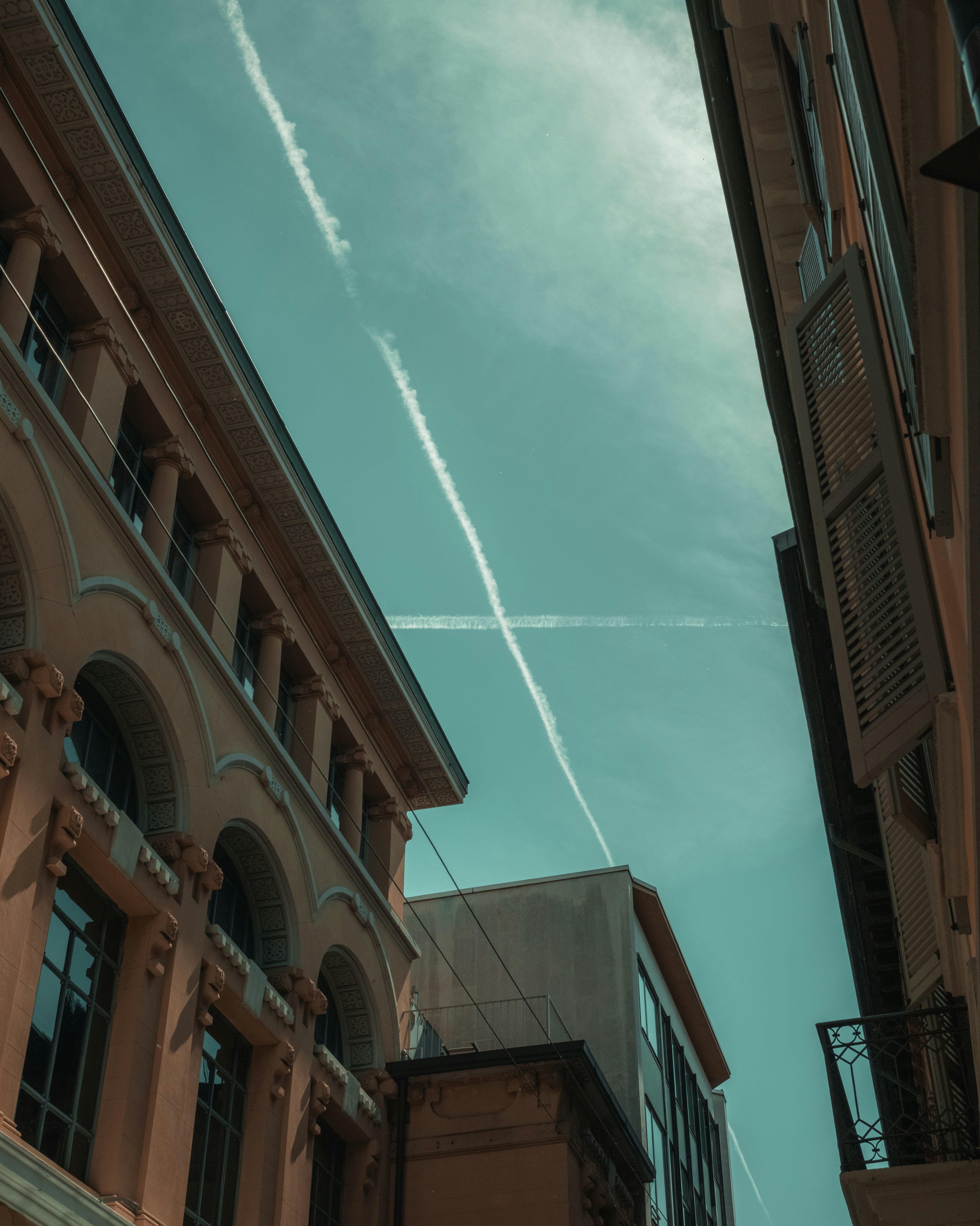 Crossing Lines: Skybound Contrails Between Historic Facades