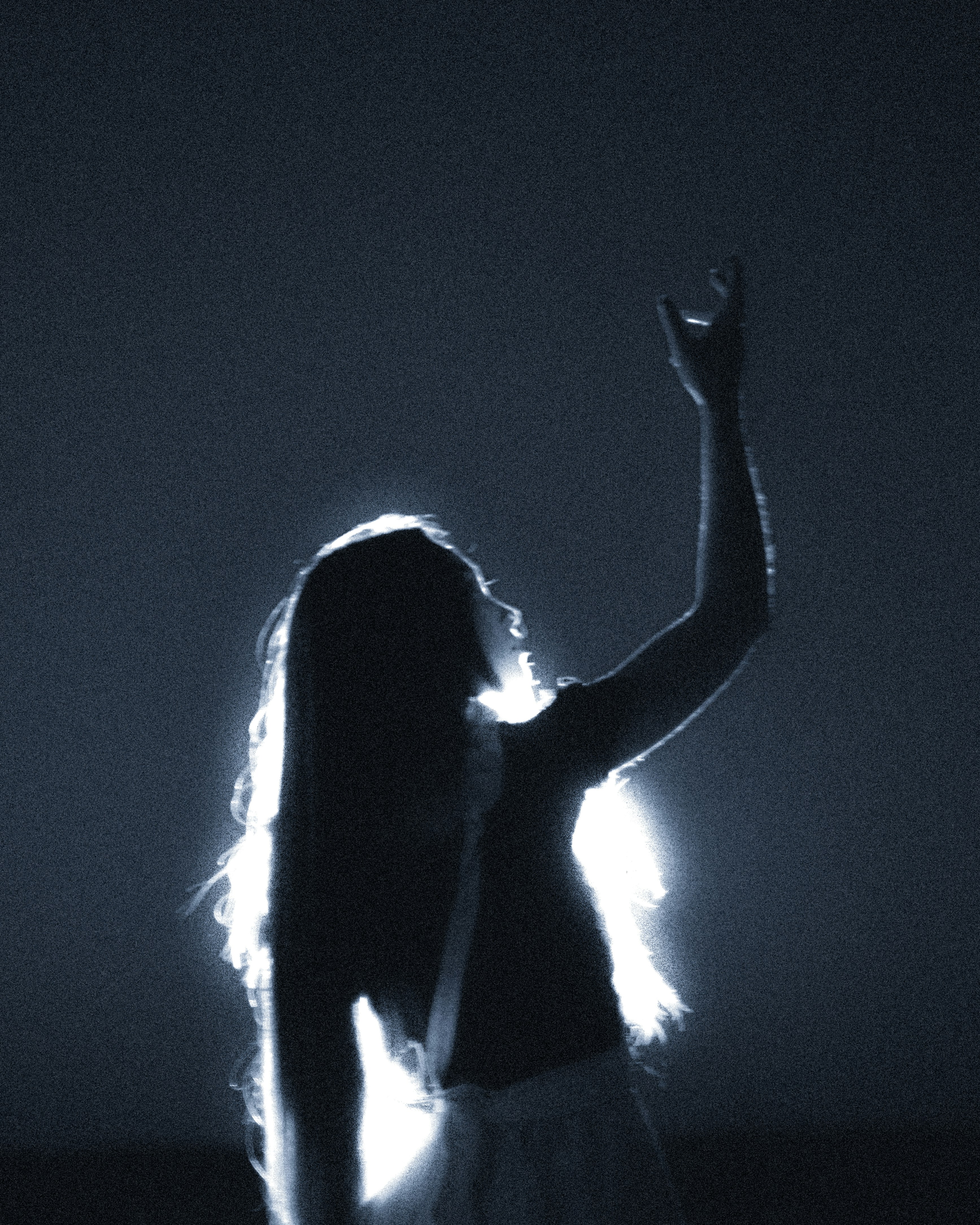 Silhouette under Nightfall: A lone figure raises a glowing hand