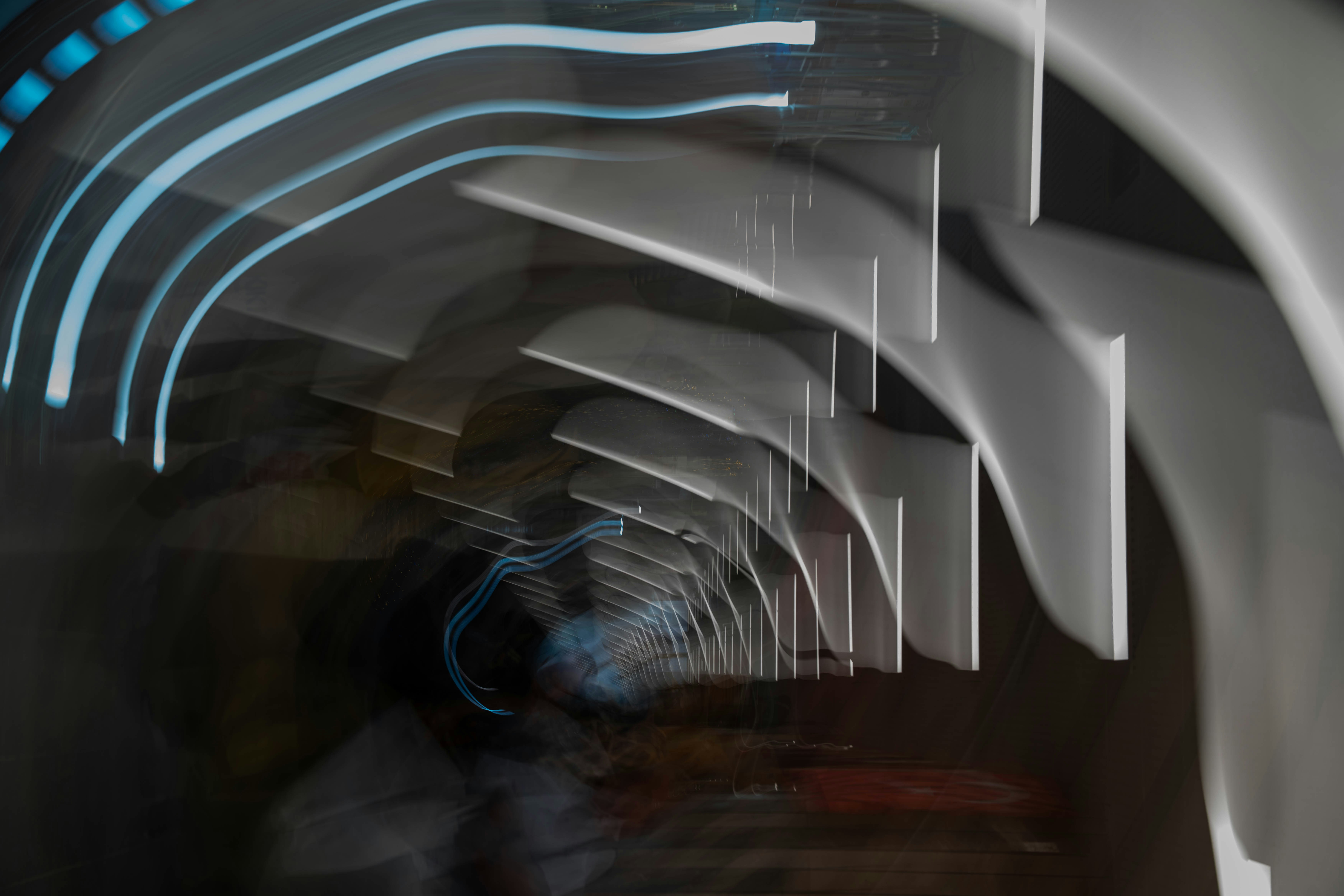 Motion-blurred tunnel with glowing arc lines guiding toward a distant vanishing point; an abstract, architectural glow-in-the-dark scene with soft reflections and geometric shapes.
