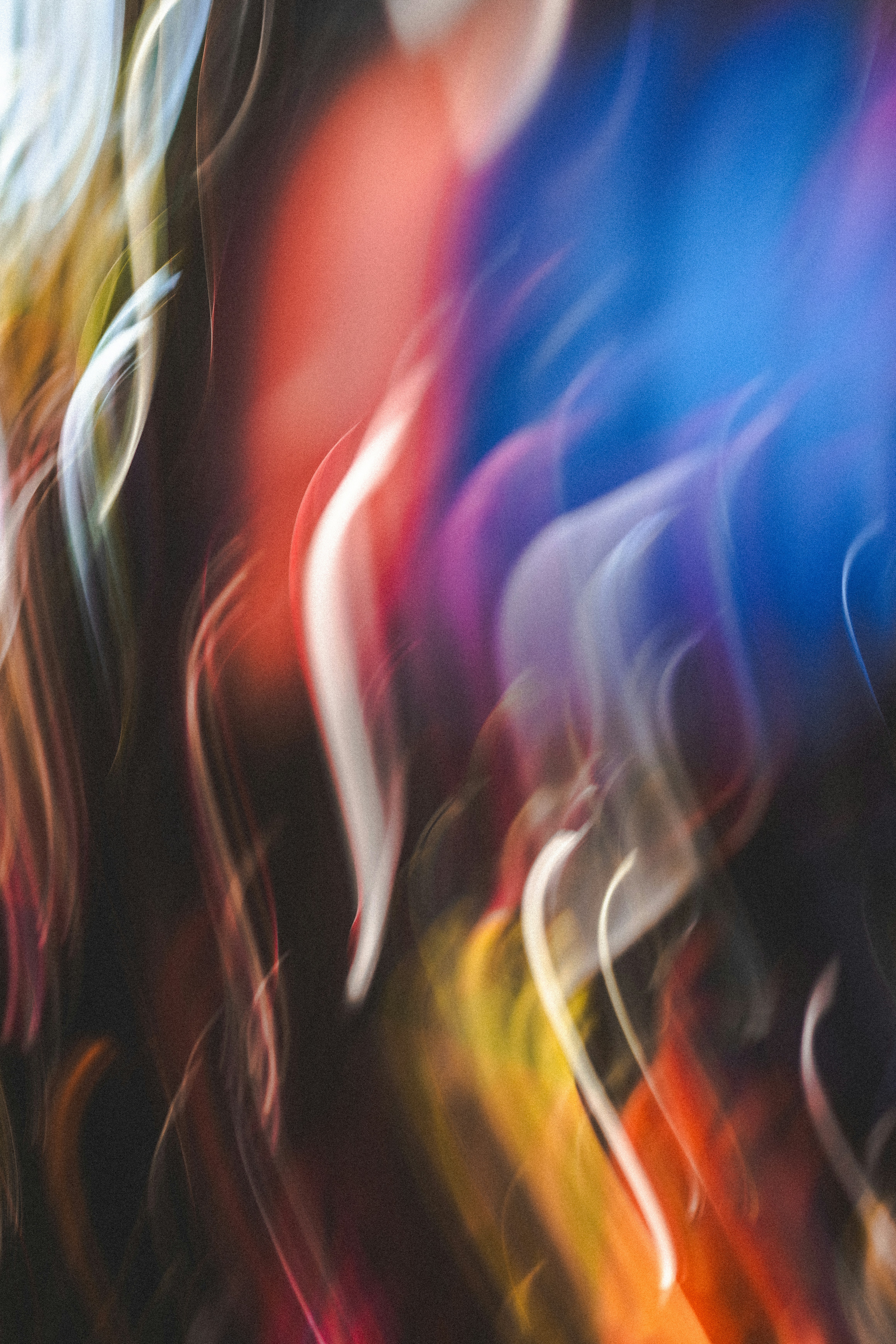 Vibrant, blurred light trails swirl across the frame in a dynamic abstract composition. The image emphasizes color, motion, and texture rather than a defined subject.