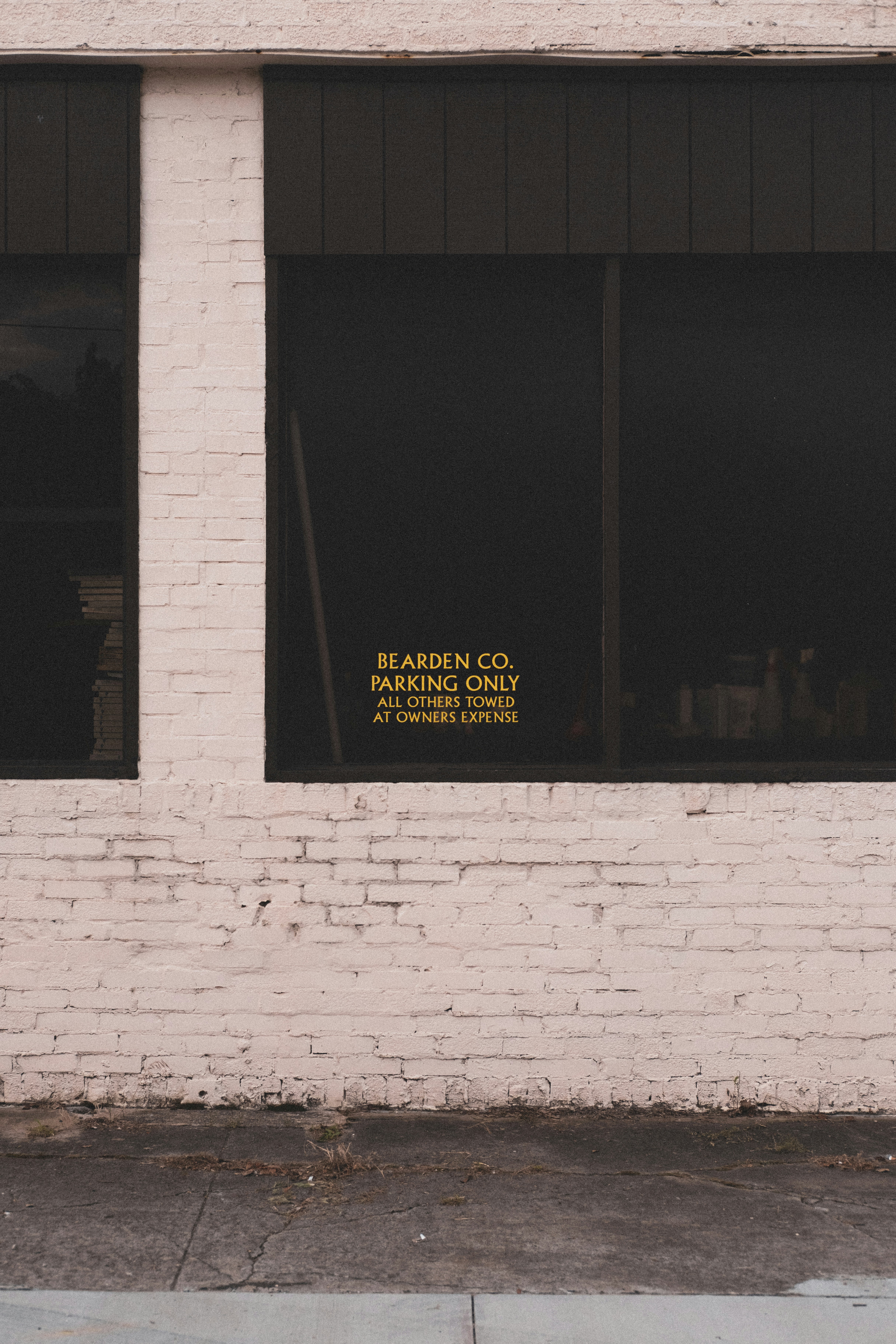 White brick storefront with dark window panes; small yellow text sign reads Bearden Co. Parking Only.
