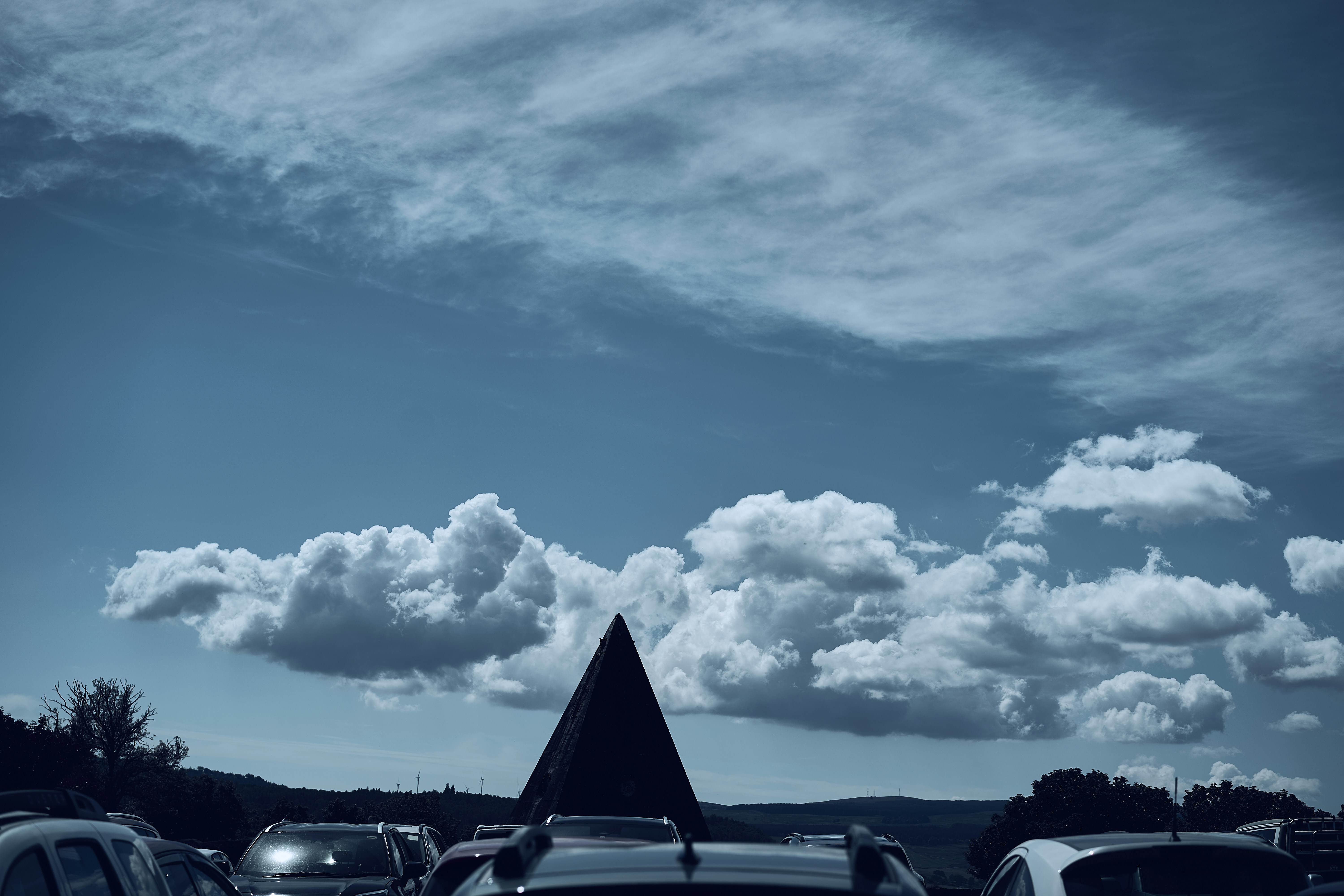 The Quiet Peak: A Pyramid Marker Above a Car-Lined Horizon