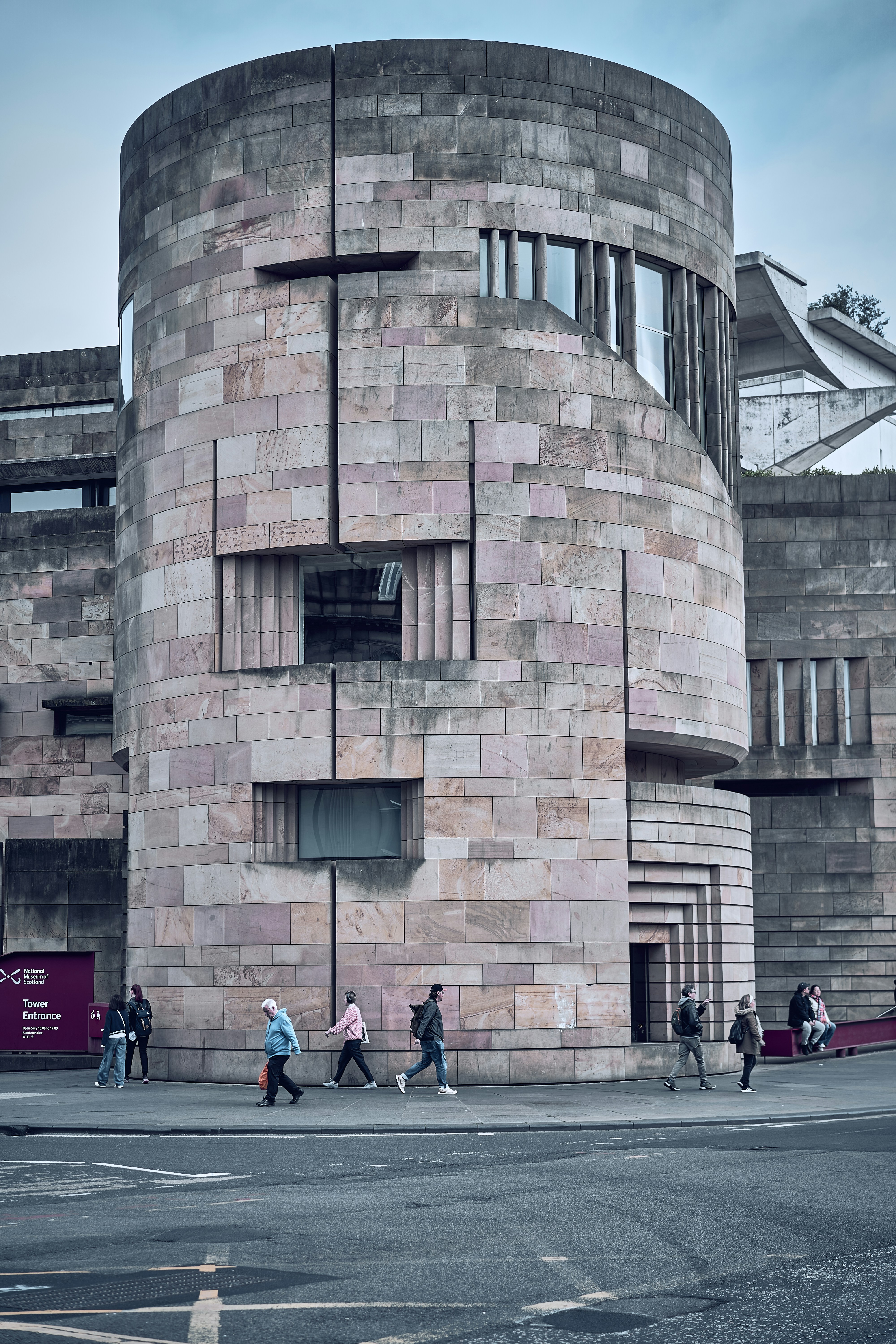 Curved Facade of a Stone Tower: People Scale the Urban Monument