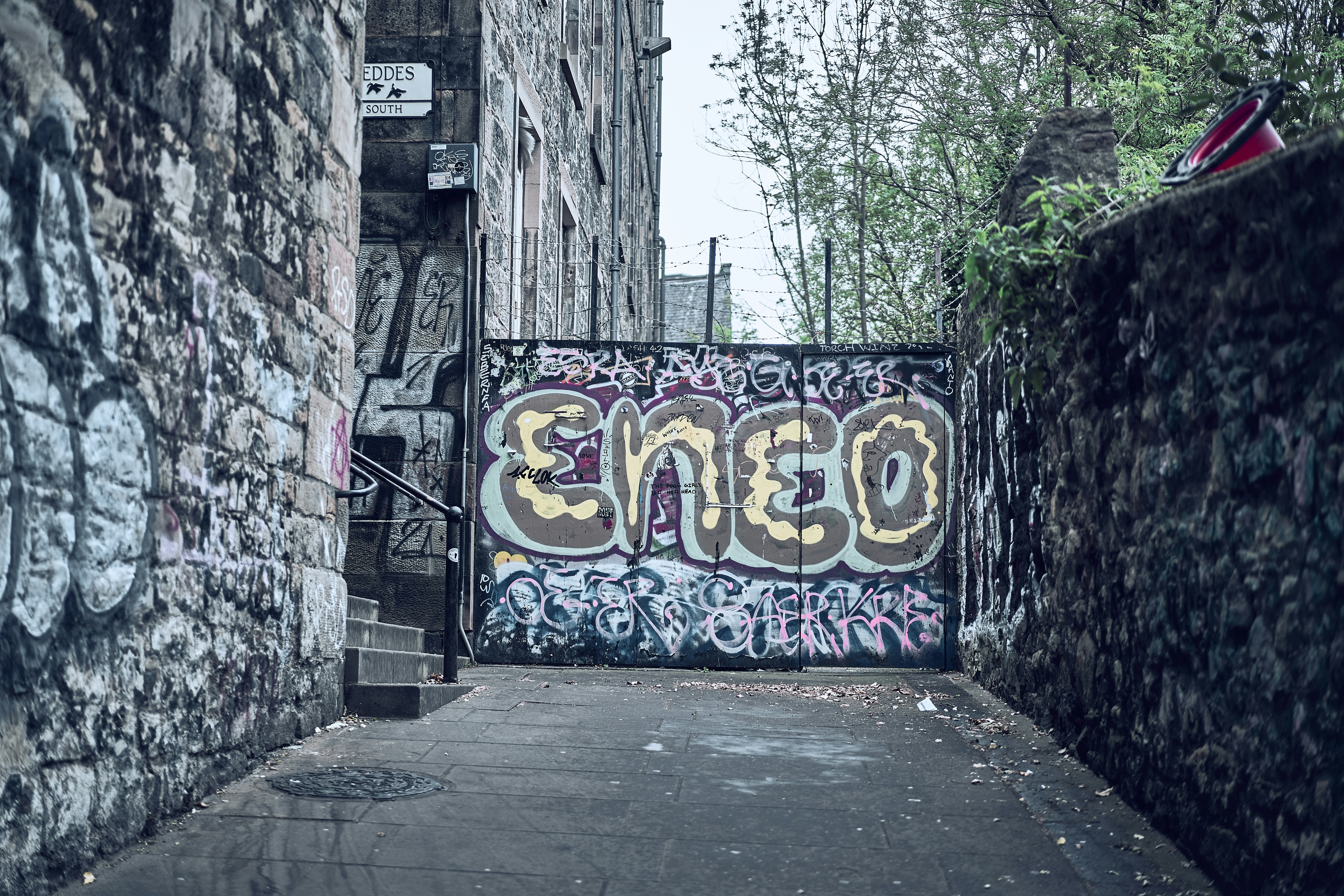 Graffiti Gateway: A Narrow Alley Framed by Weathered Brick and Stone