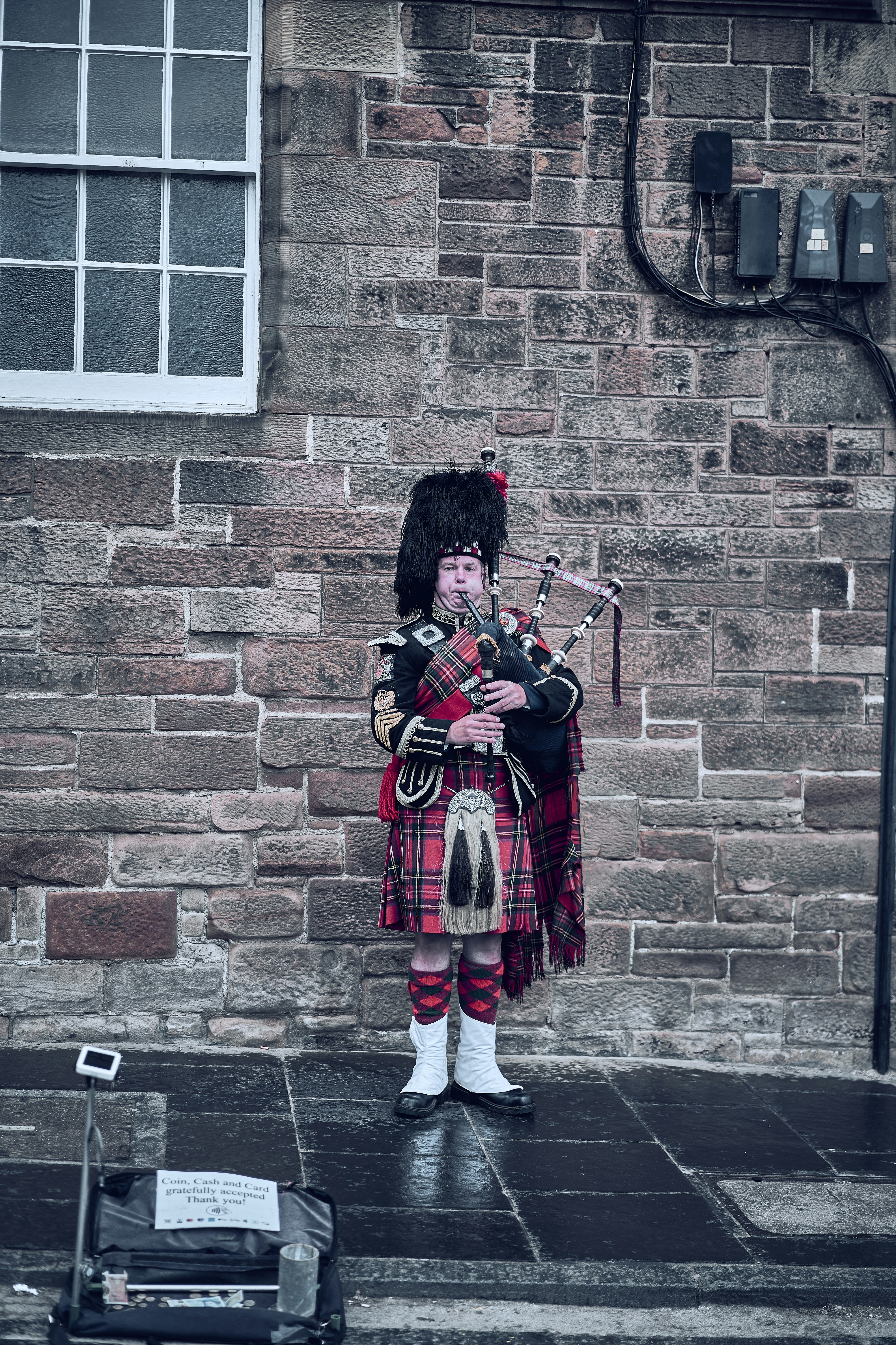 Highland Piper in a Plaid Presence Against a Stone Facade