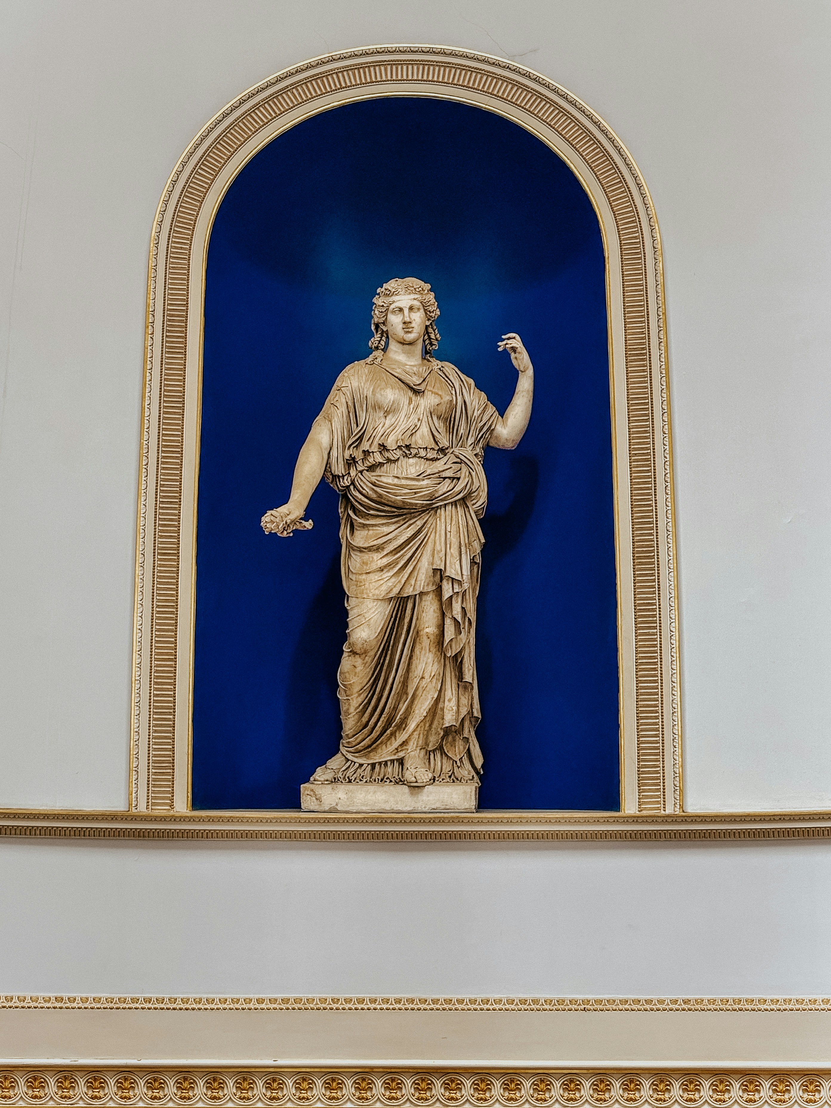 Statue of a draped goddess framed by a gold-ornamented arch