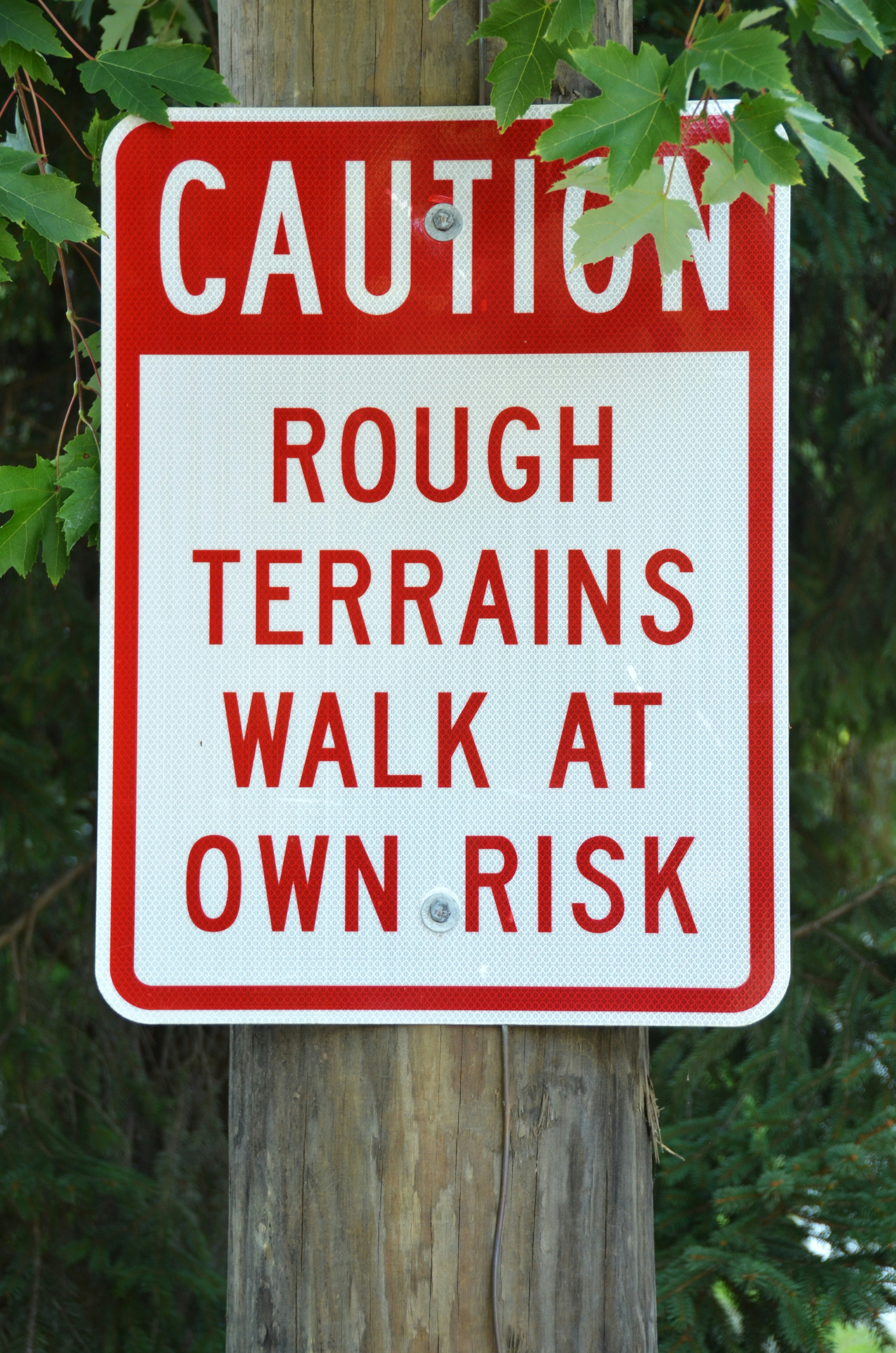 Caution Sign on Weathered Post: Rough Terrain Ahead
