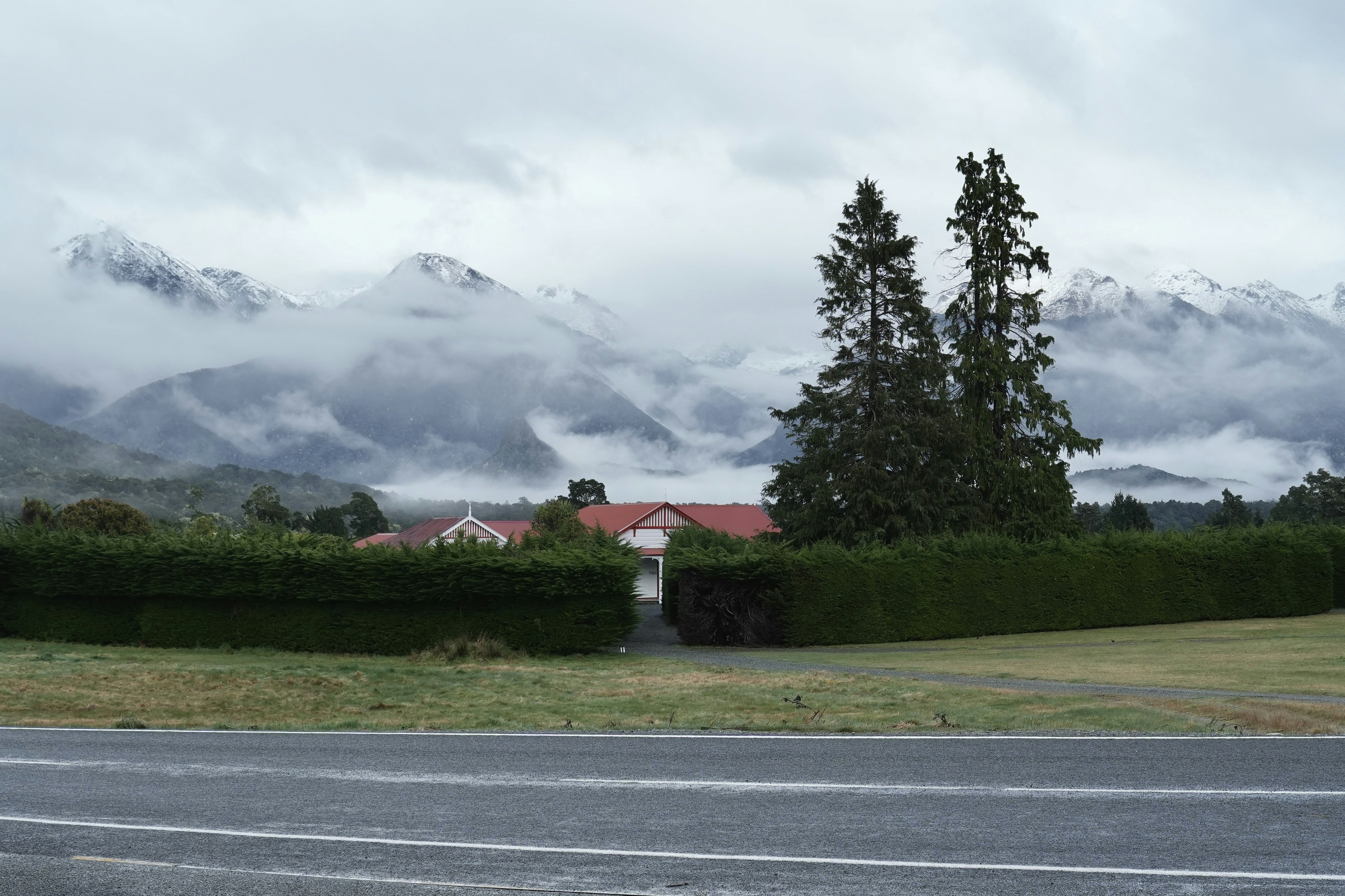 Misty foothills framed by trimmed hedges and a distant red-roofed center