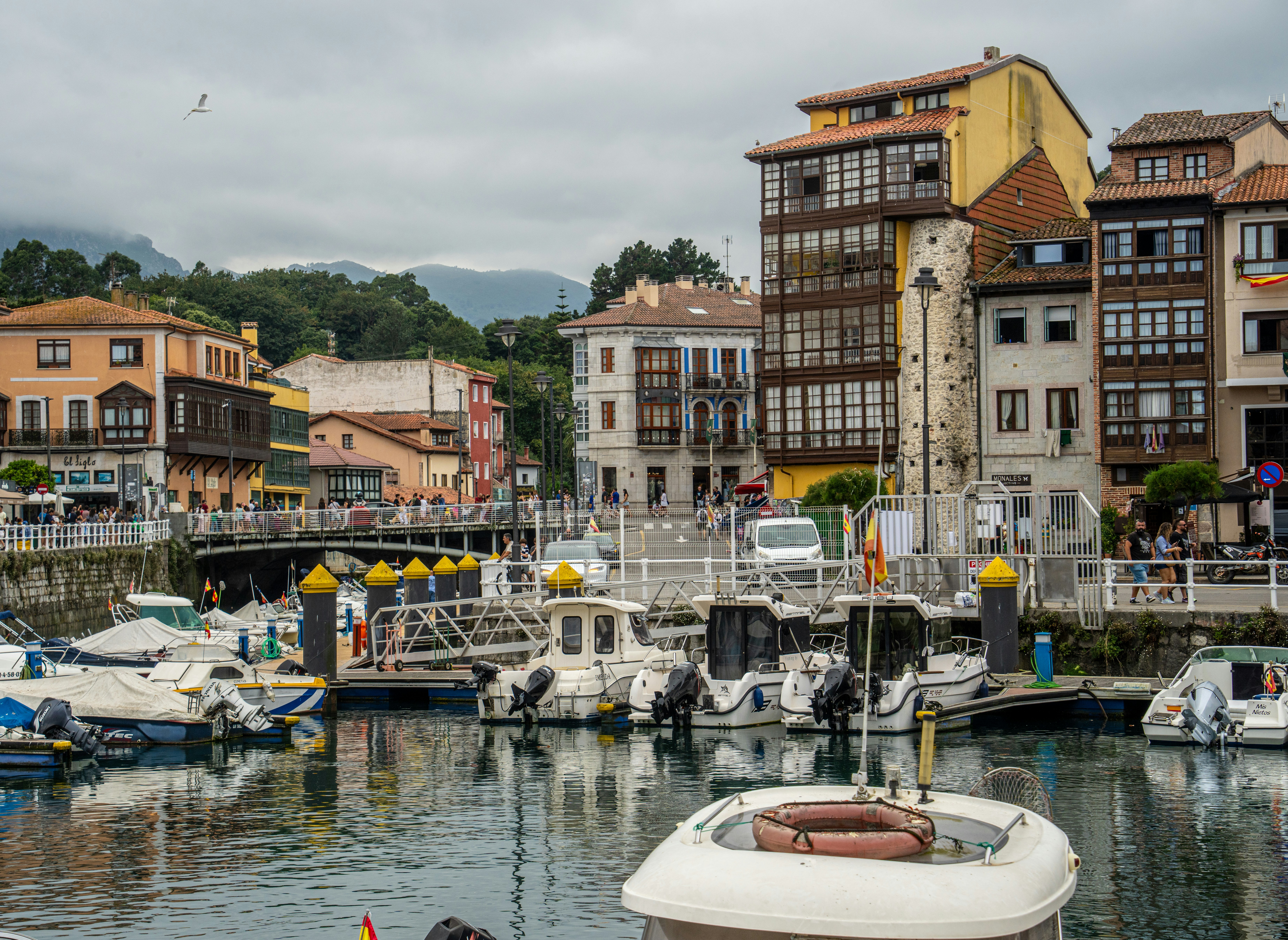 Colorful multi-story buildings line a harbor with boats docked and calm water reflecting the scene.
