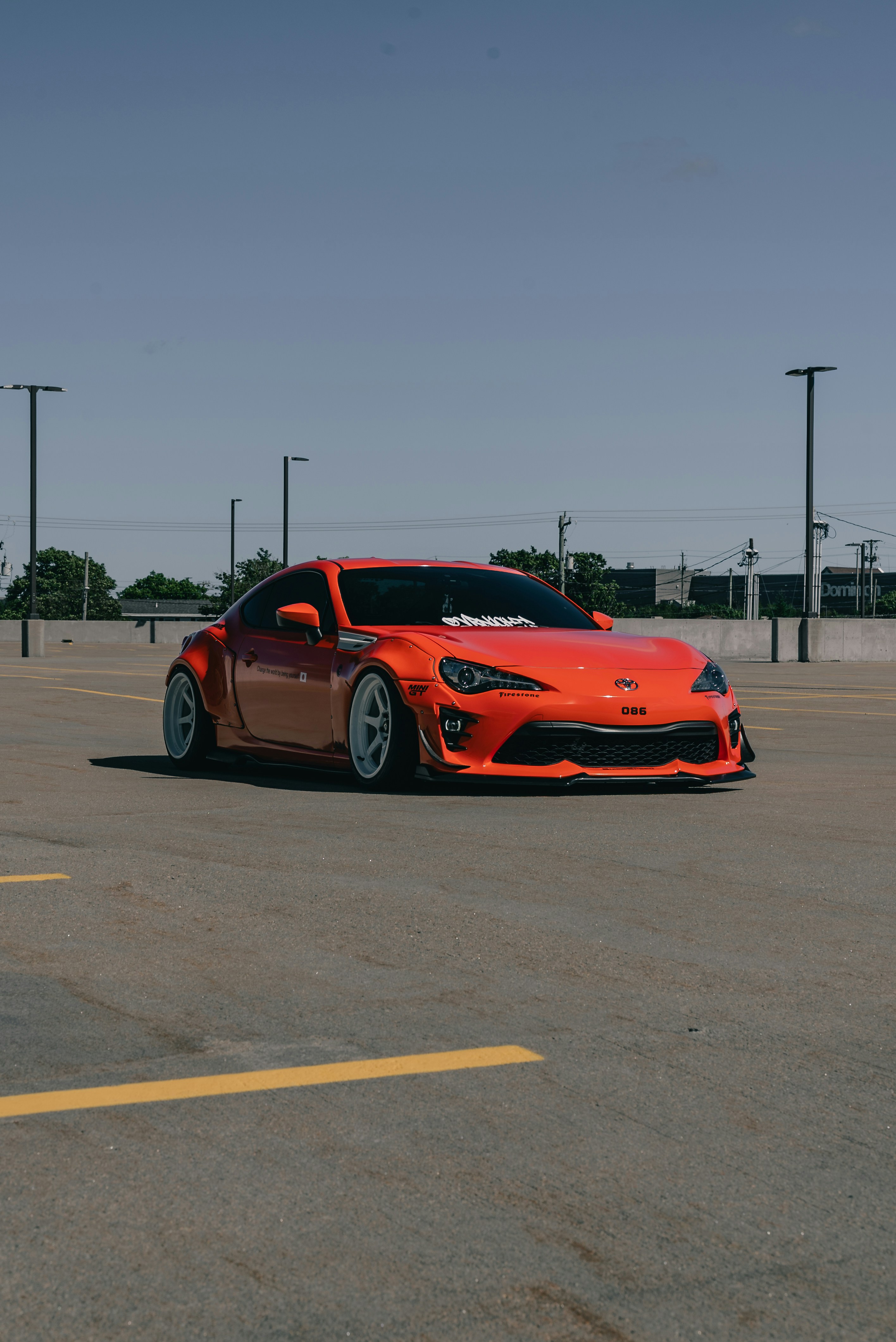 Low-angle orange: a tuned sports coupe anchors an empty rooftop lot
