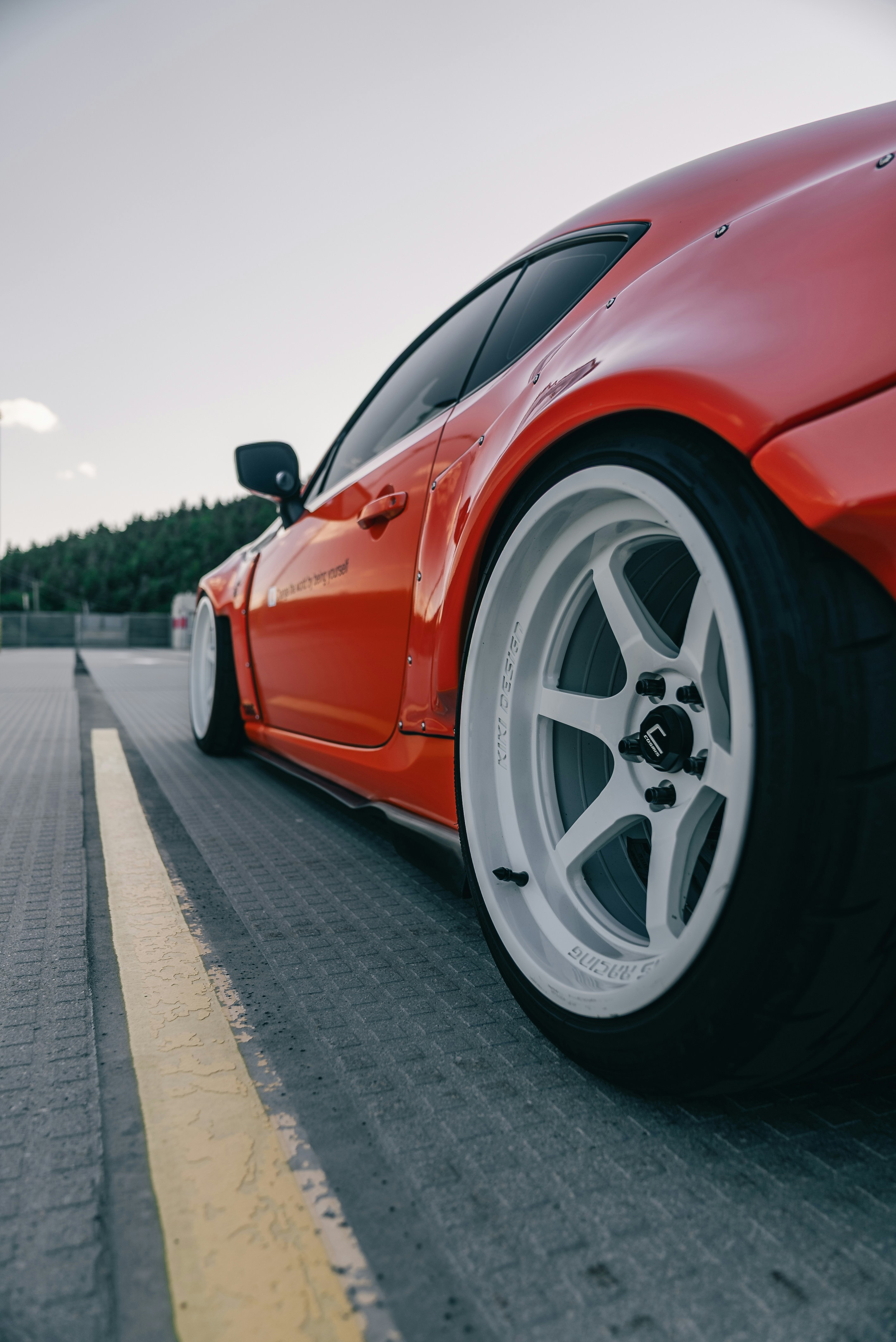 Low-angle red racer: a close-up on the wheel and body line