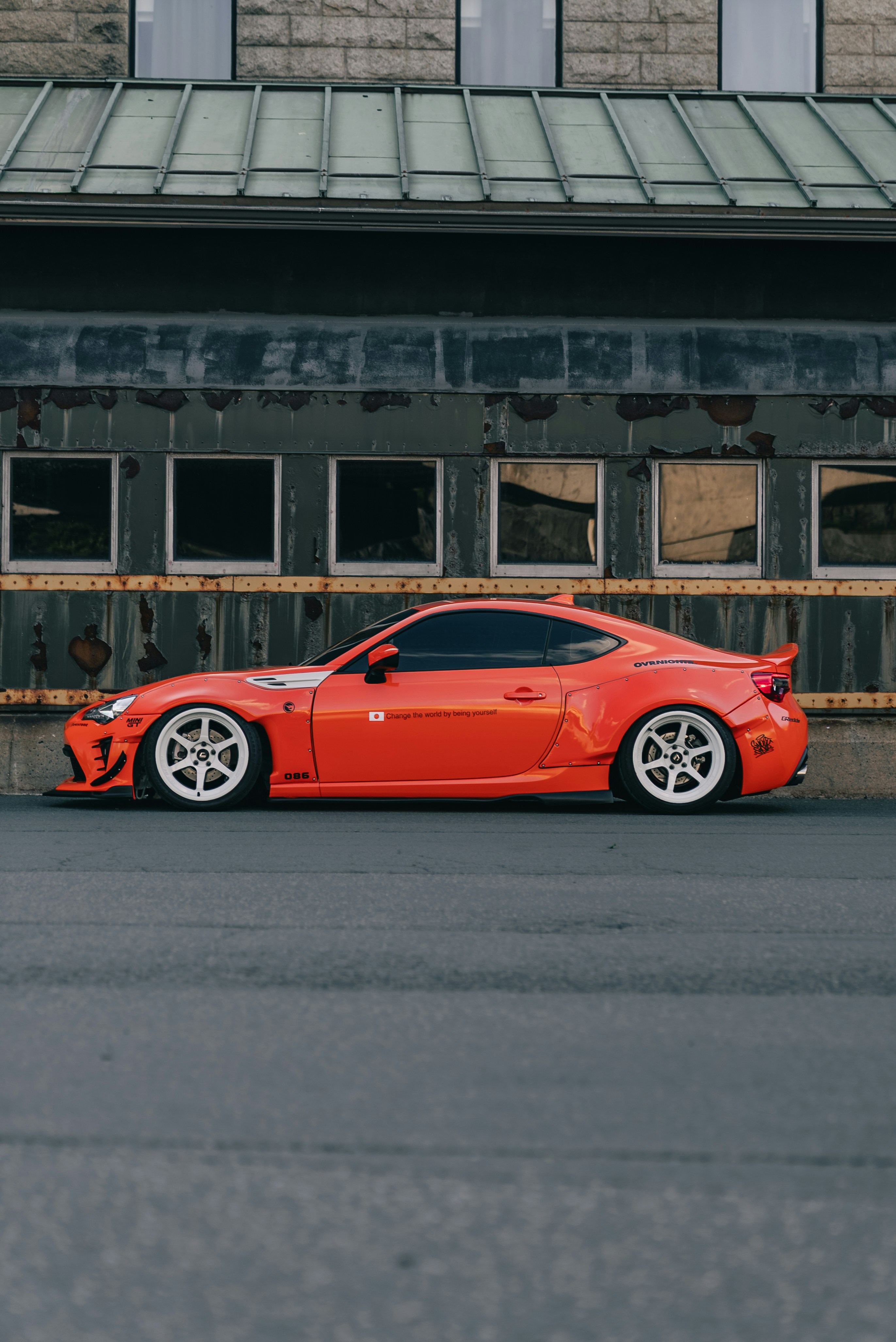 Scarlet Apex: Low-Slung Red Roto Horse Resting Before Industrial Steel