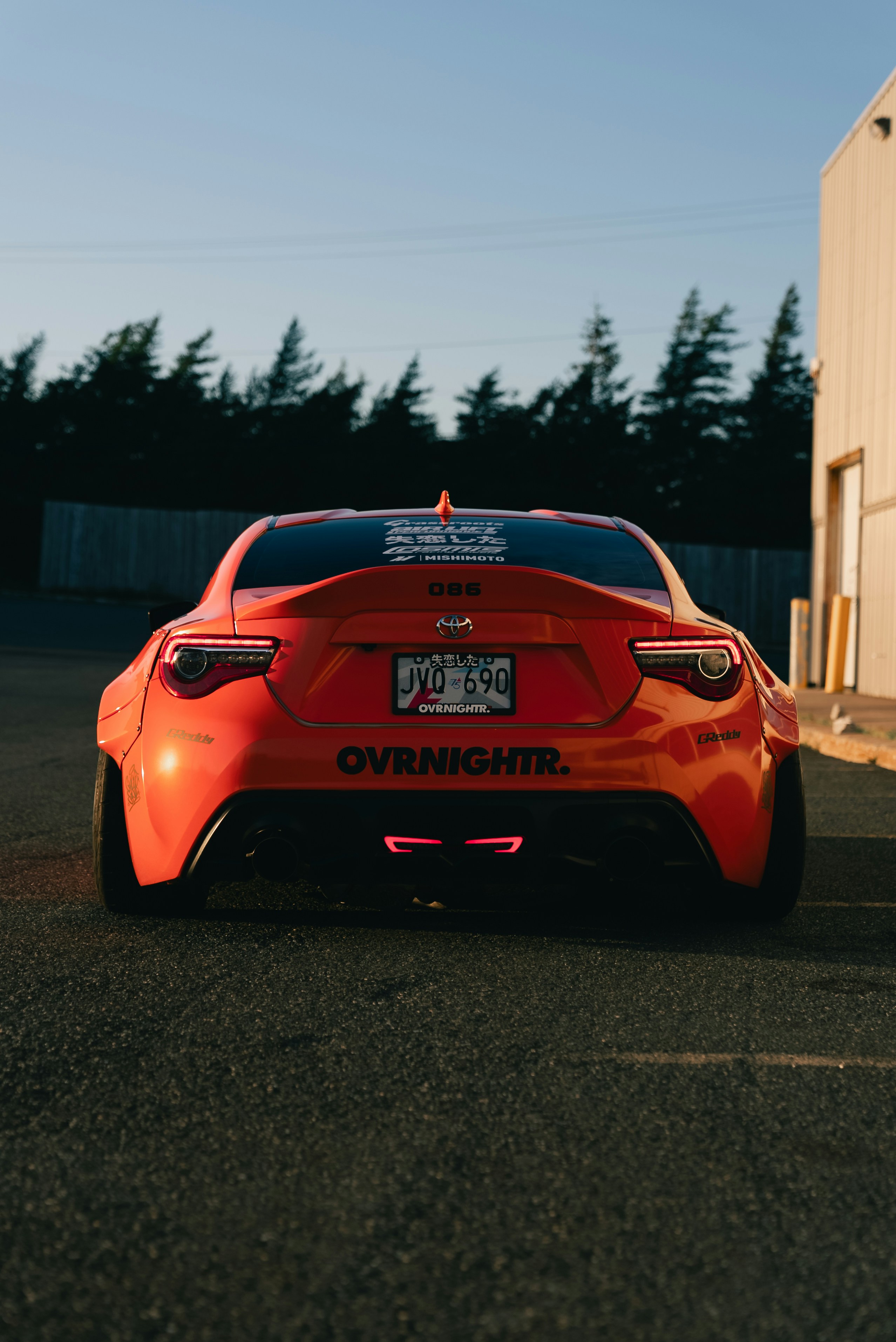 Rear-view of a Bright Orange Sports Coupe with OVRNIGHTR Branding