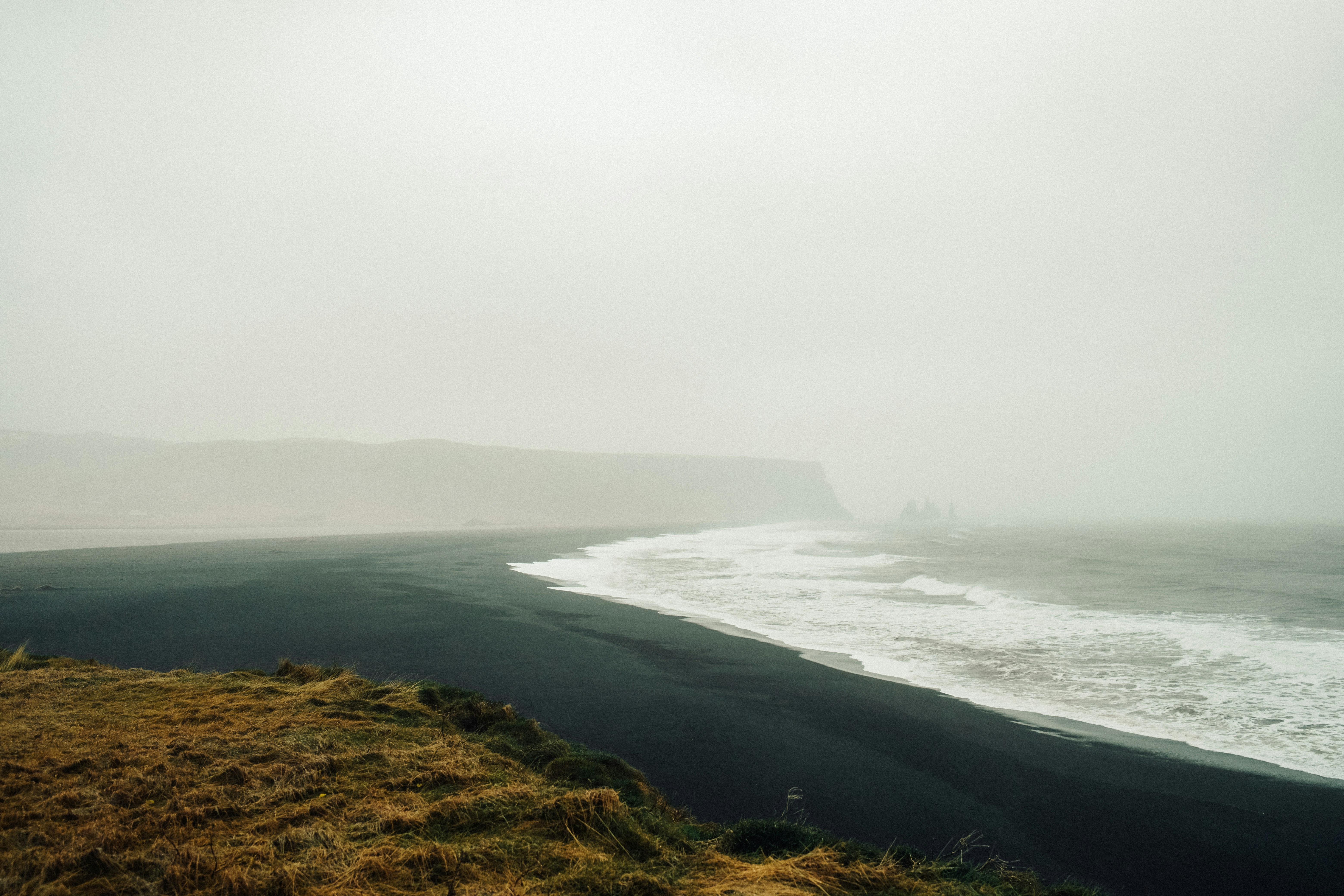 Misty shoreline fades into horizon under quiet cliffs