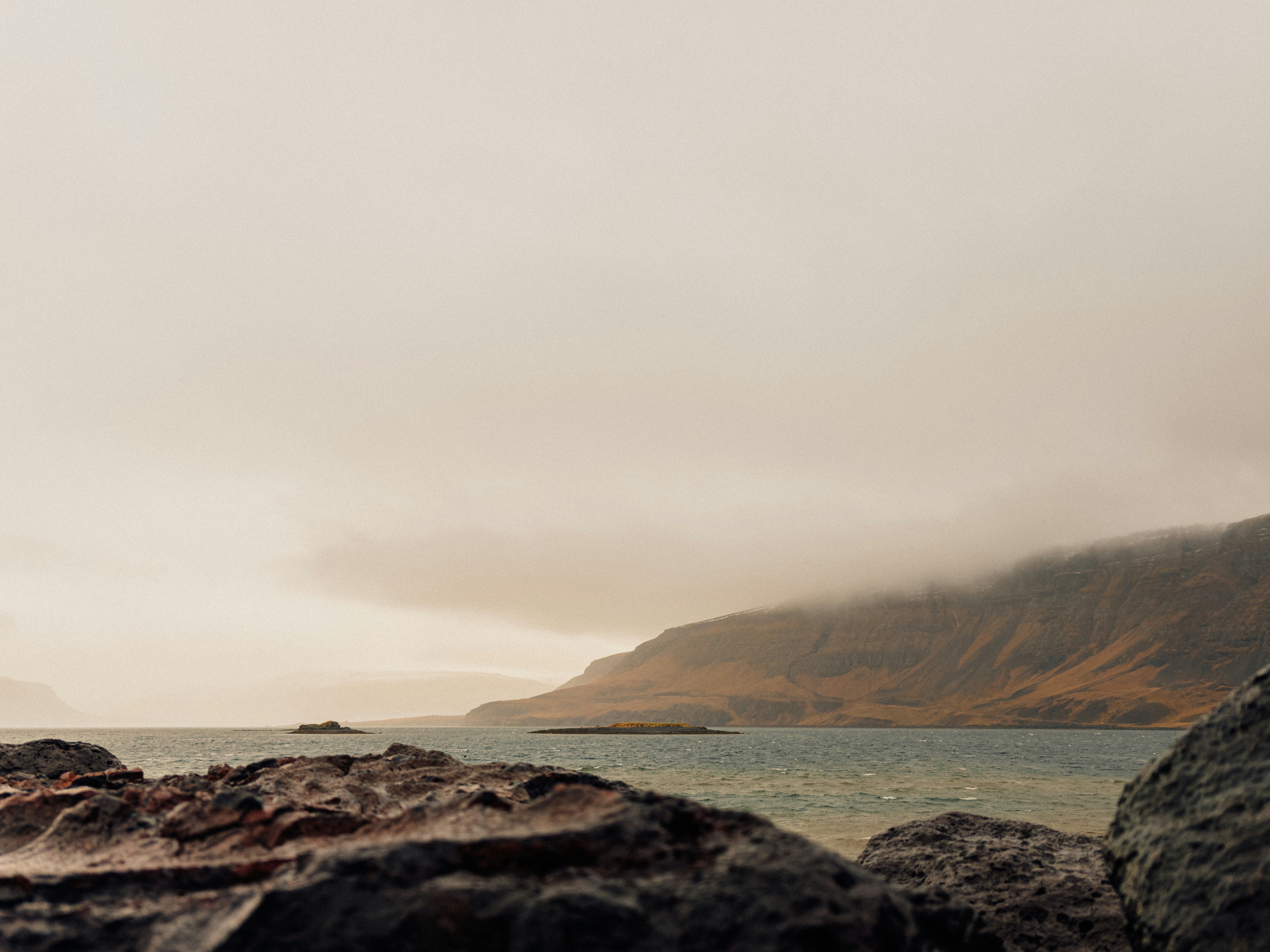Mist over basalt shoreline: distant cliffs meet a calm sea