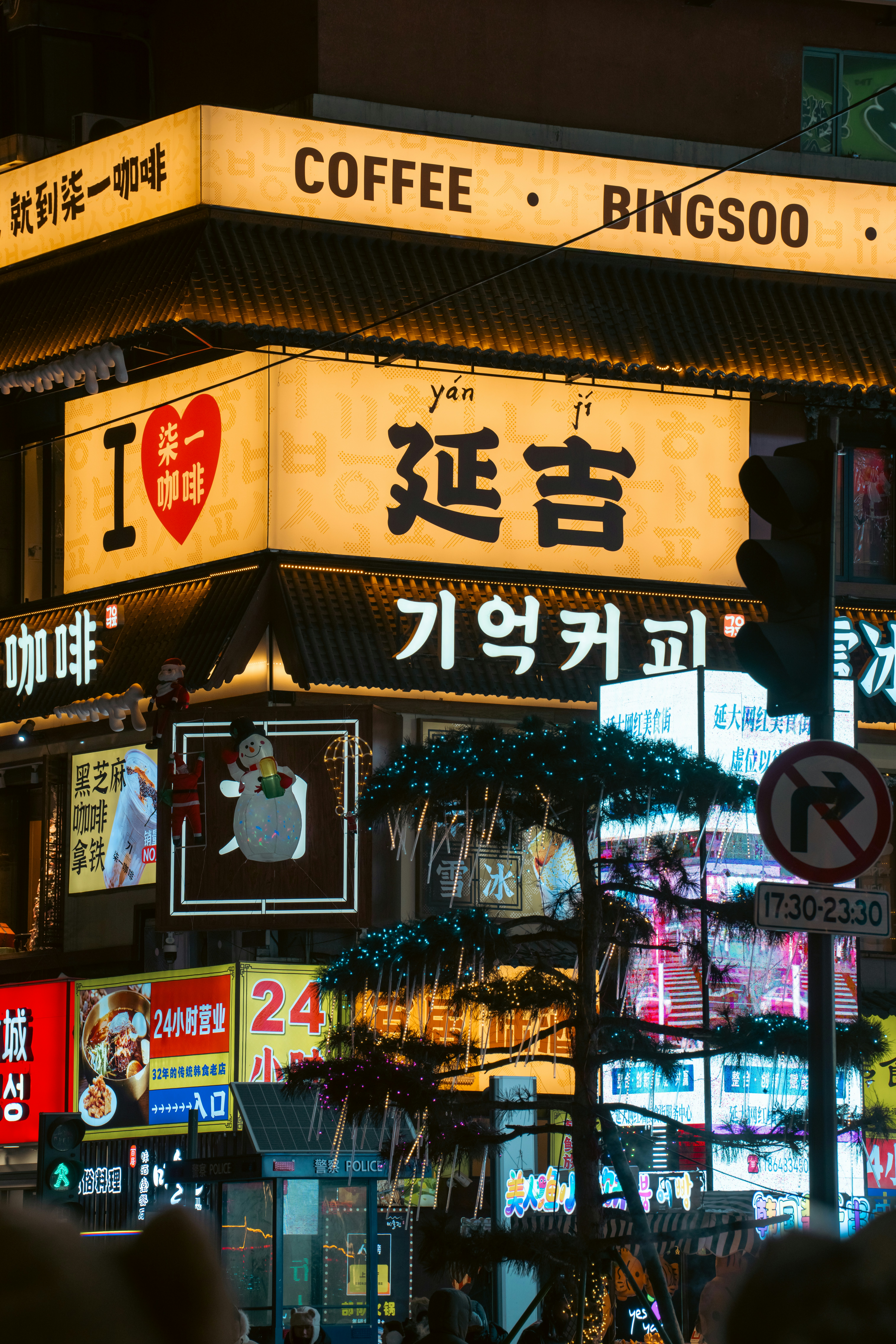 Illuminated signs for a coffee shop in Yanji with a tree in the foreground