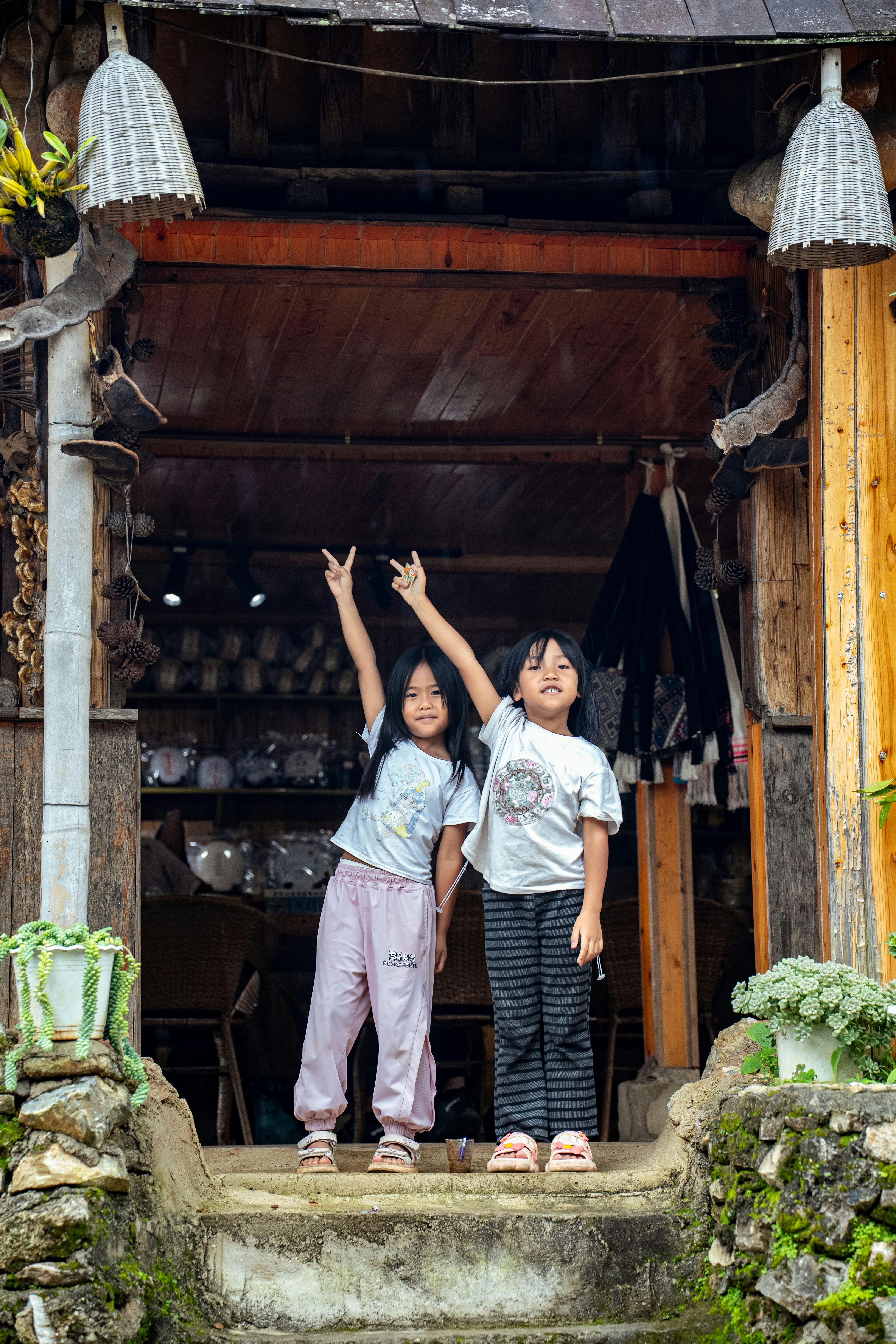 Two playful sisters pose at the threshold of a rustic doorway