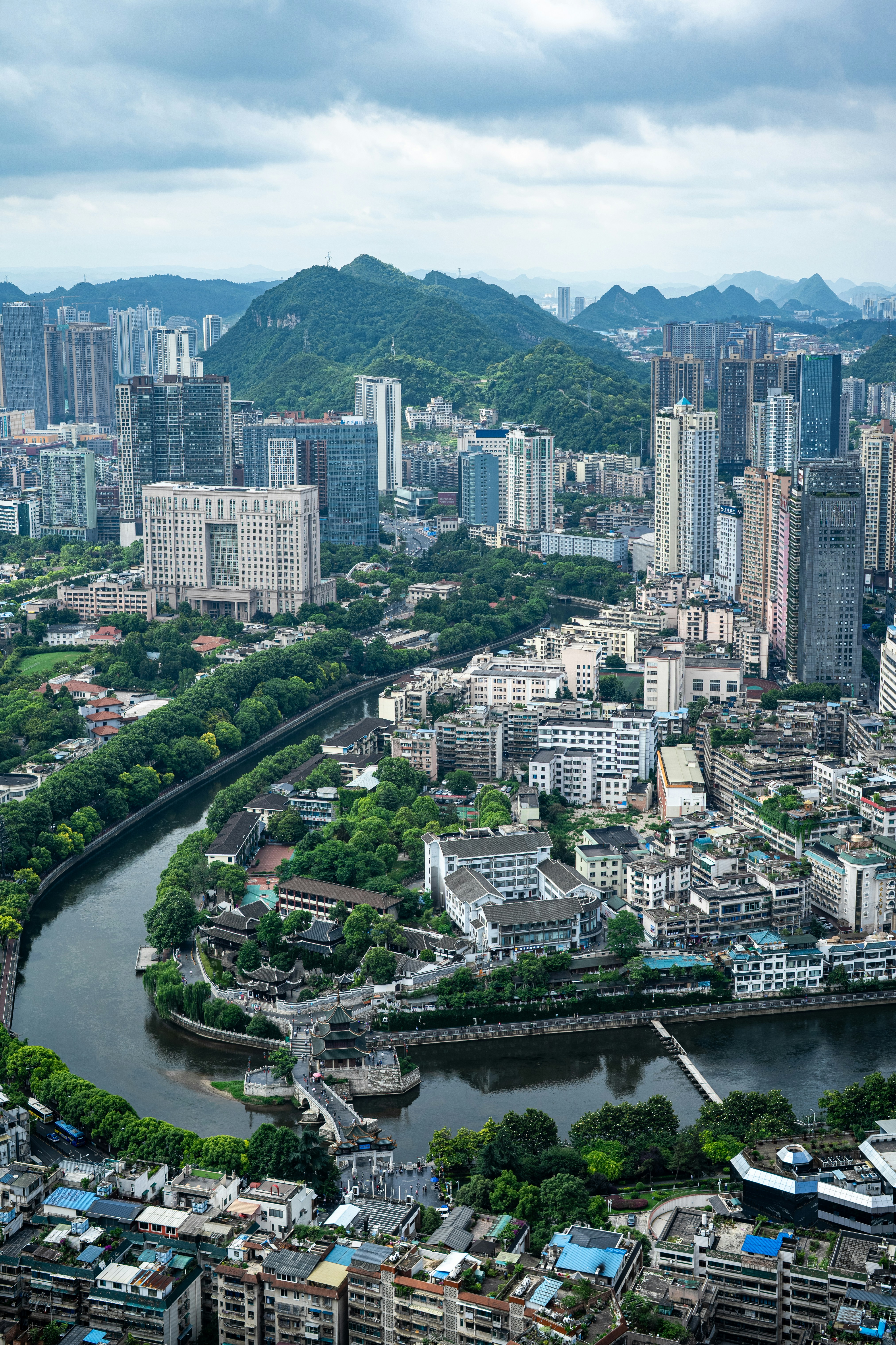 Riverside Crest: A Panoramic Urban Tapestry with Green Hills Backing