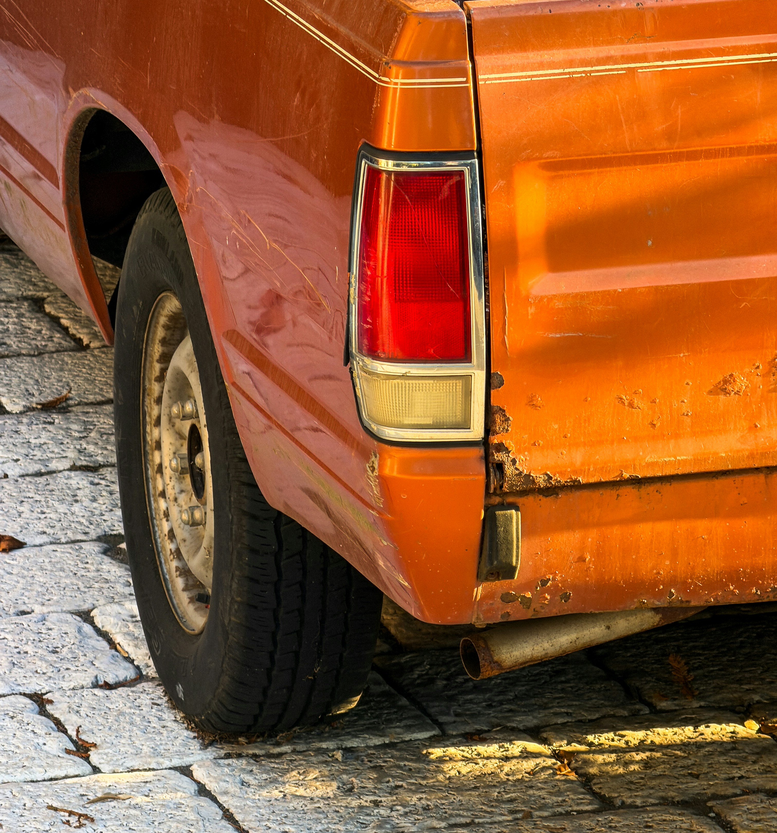 Rust and Wheels: The Back Corner of a Weathered Orange Pickup