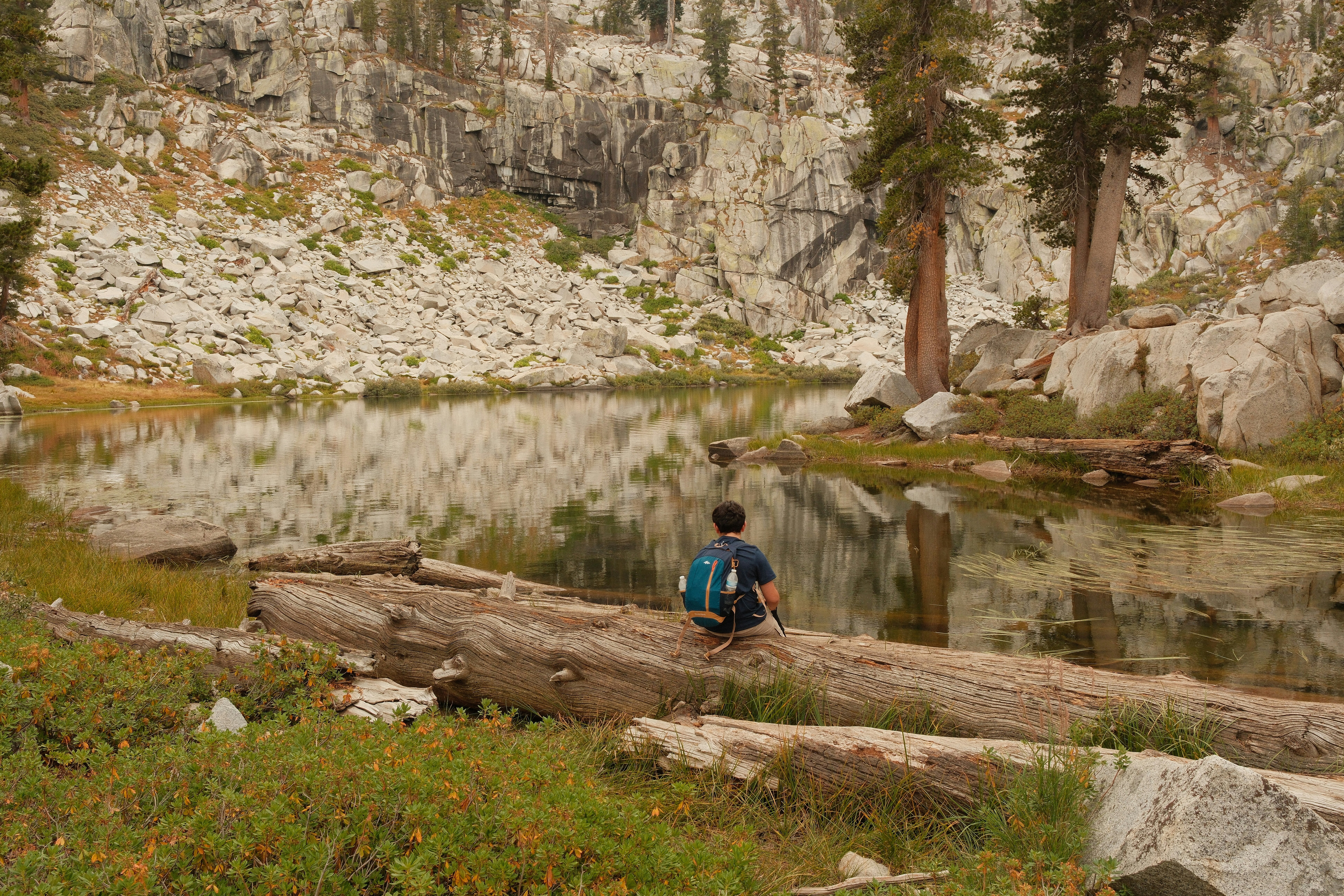 Secluded Canyon This Way: A Lone Hiker Sits by a Mirror Lake
