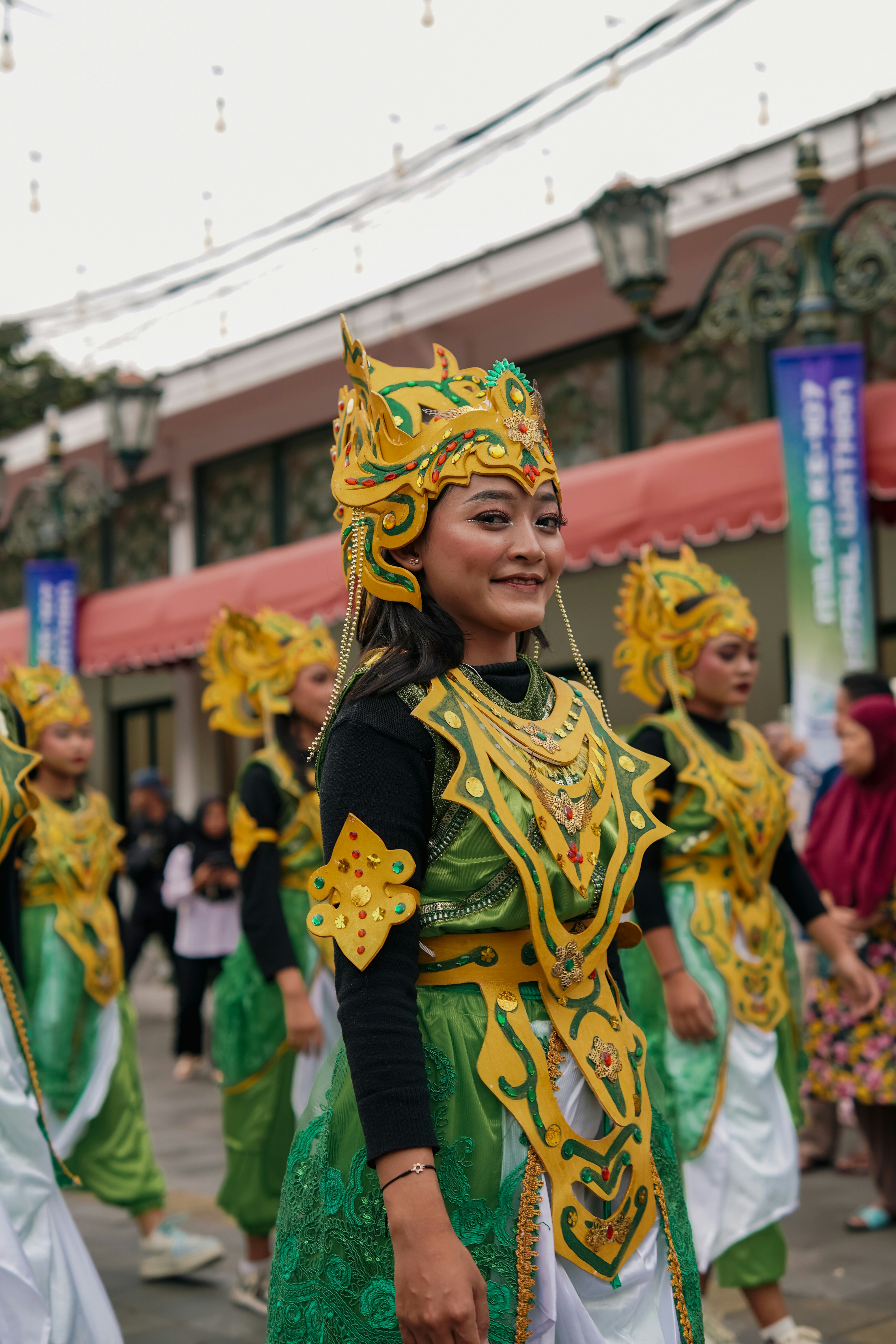 Green-and-gold festival dancer under decorative banners
