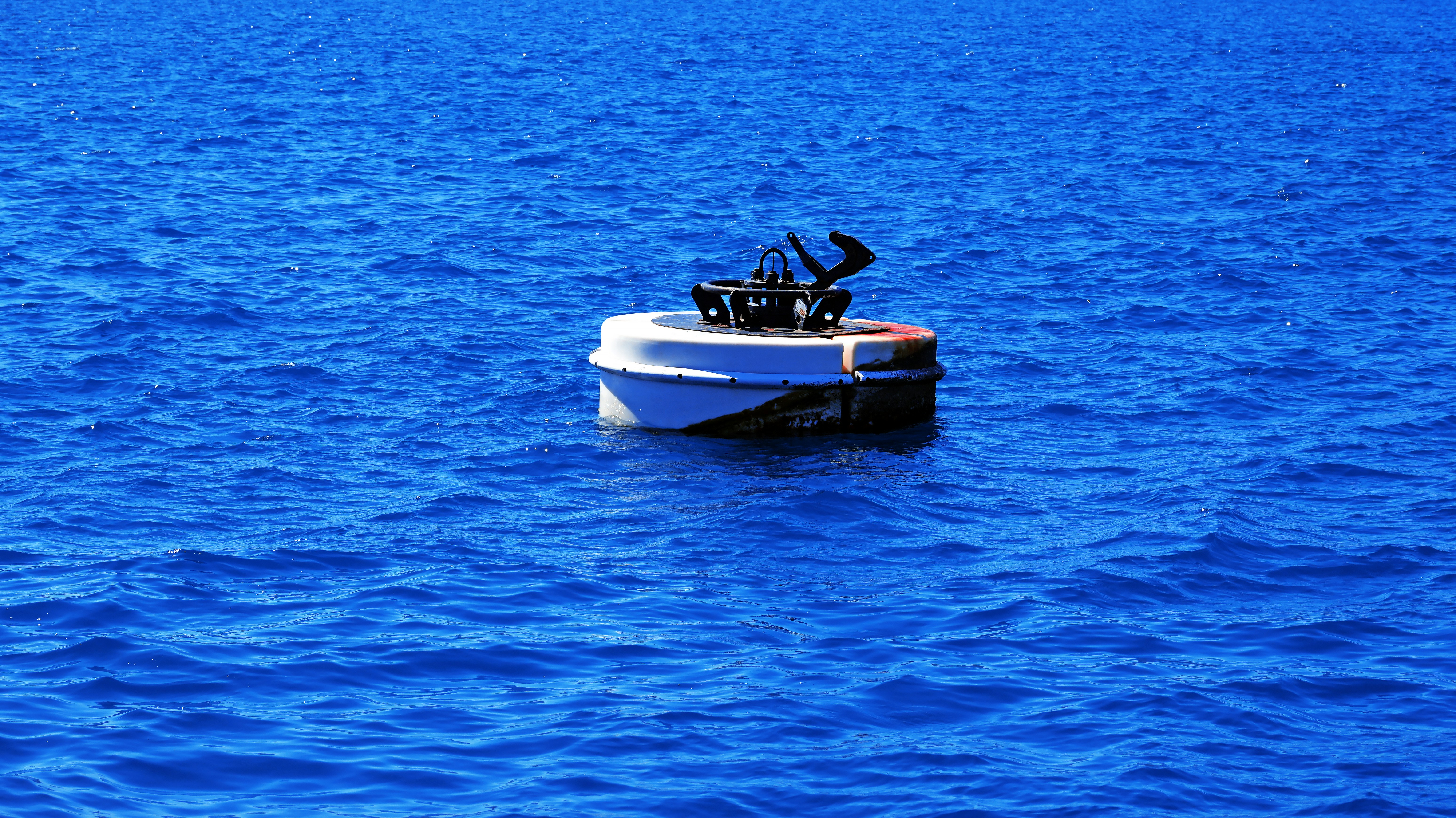 Tiny Boat, Vast Blue: A Lonely Vessel Anchored in Open Sea
