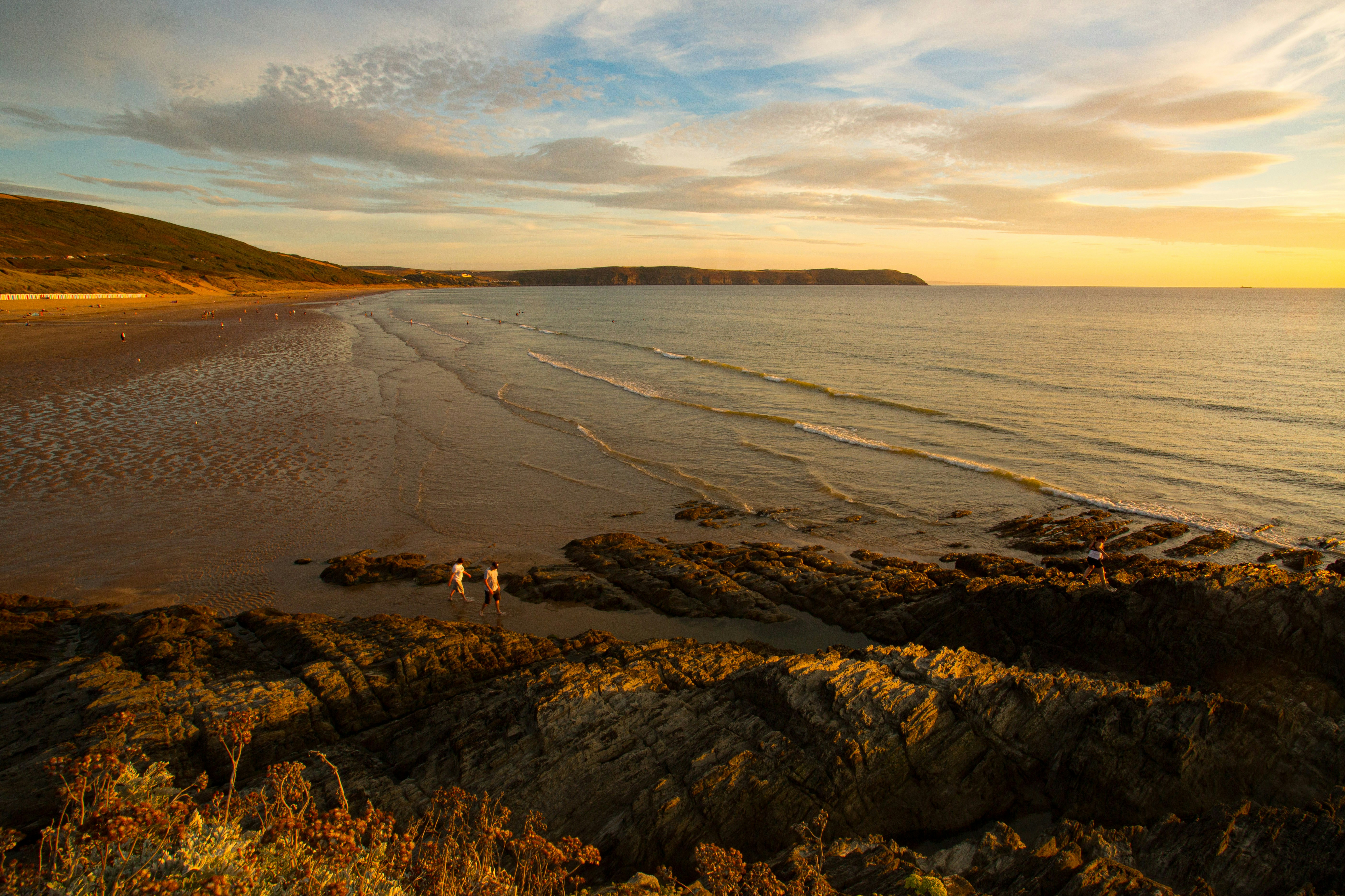 Golden Shoreline at Dusk: Quiet Waves and Cliffside Light
