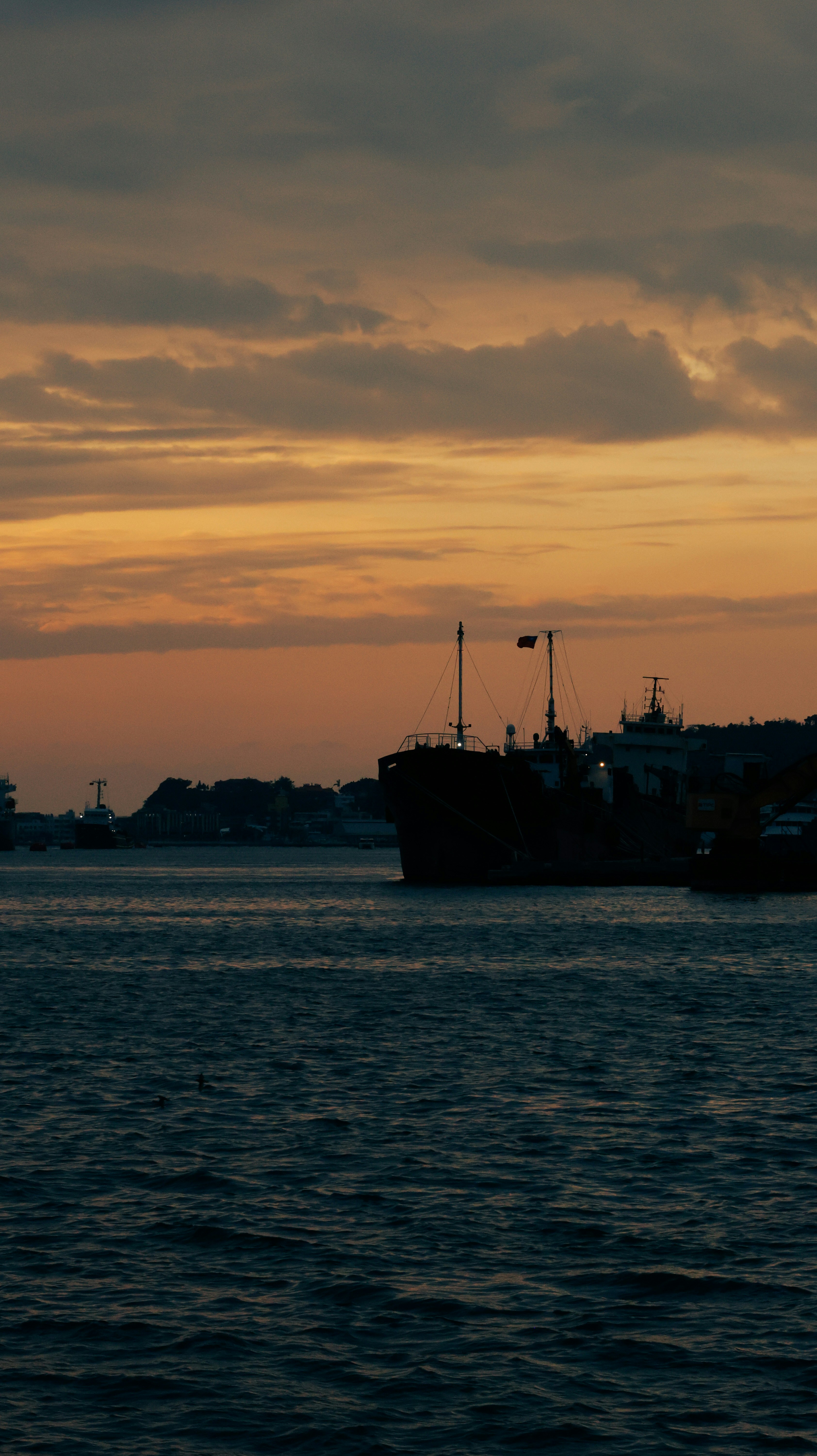 Harbor at Dusk: A Vessel Silhouette Against a Looming Sunset