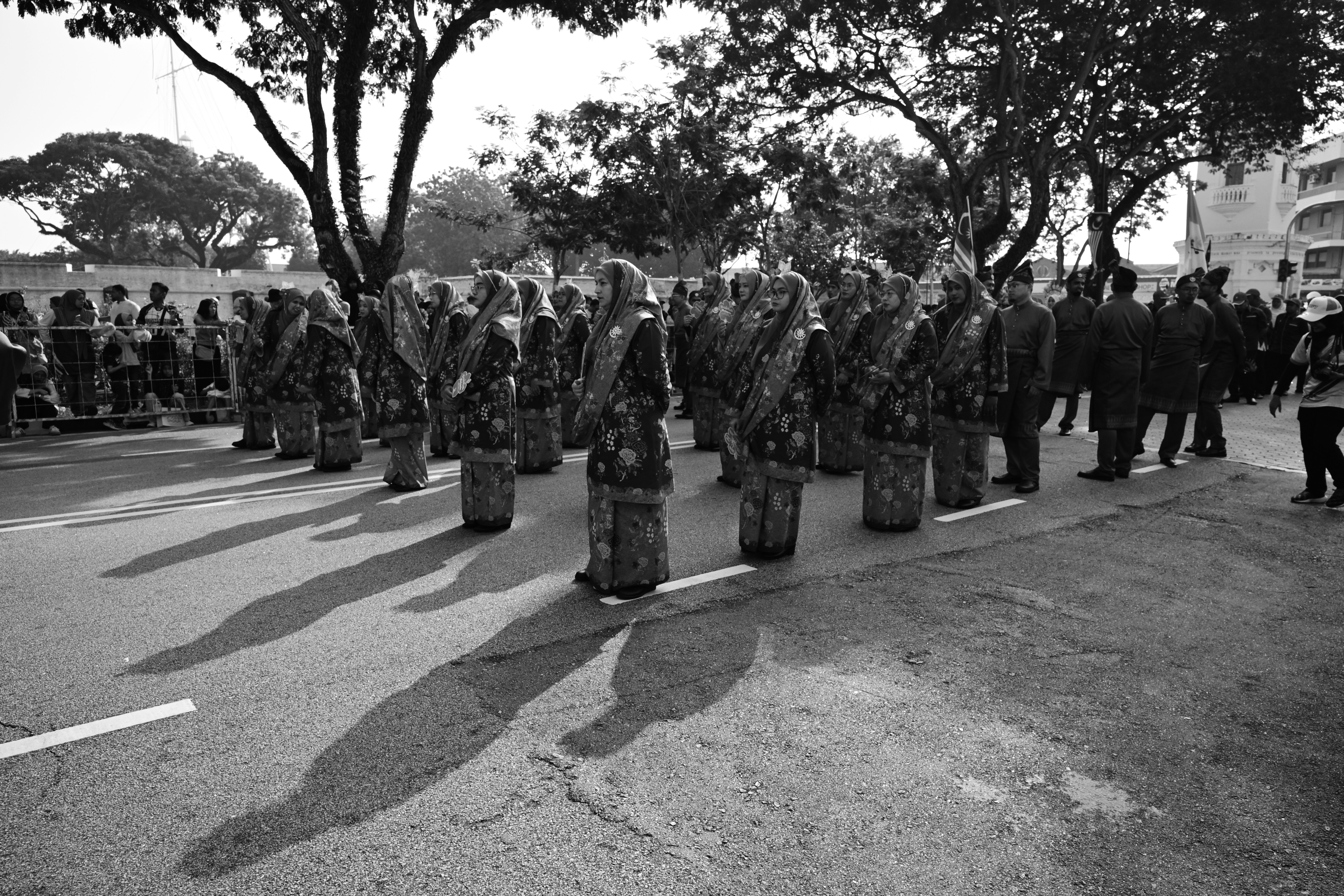 Marching Rows: Silhouettes in Uniform on a Sunlit Street