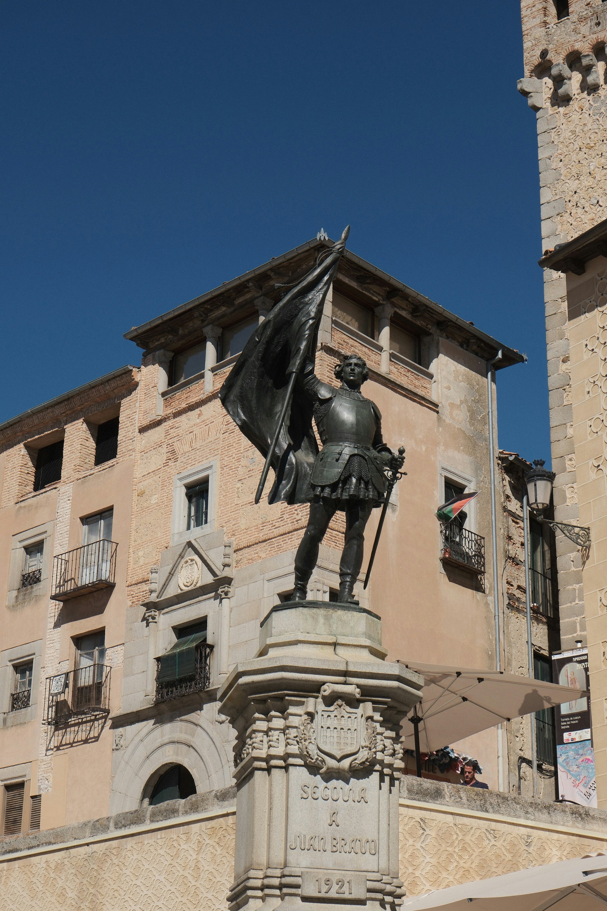 Brass Sentinel: A statue atop a carved pedestal in a sunlit plaza