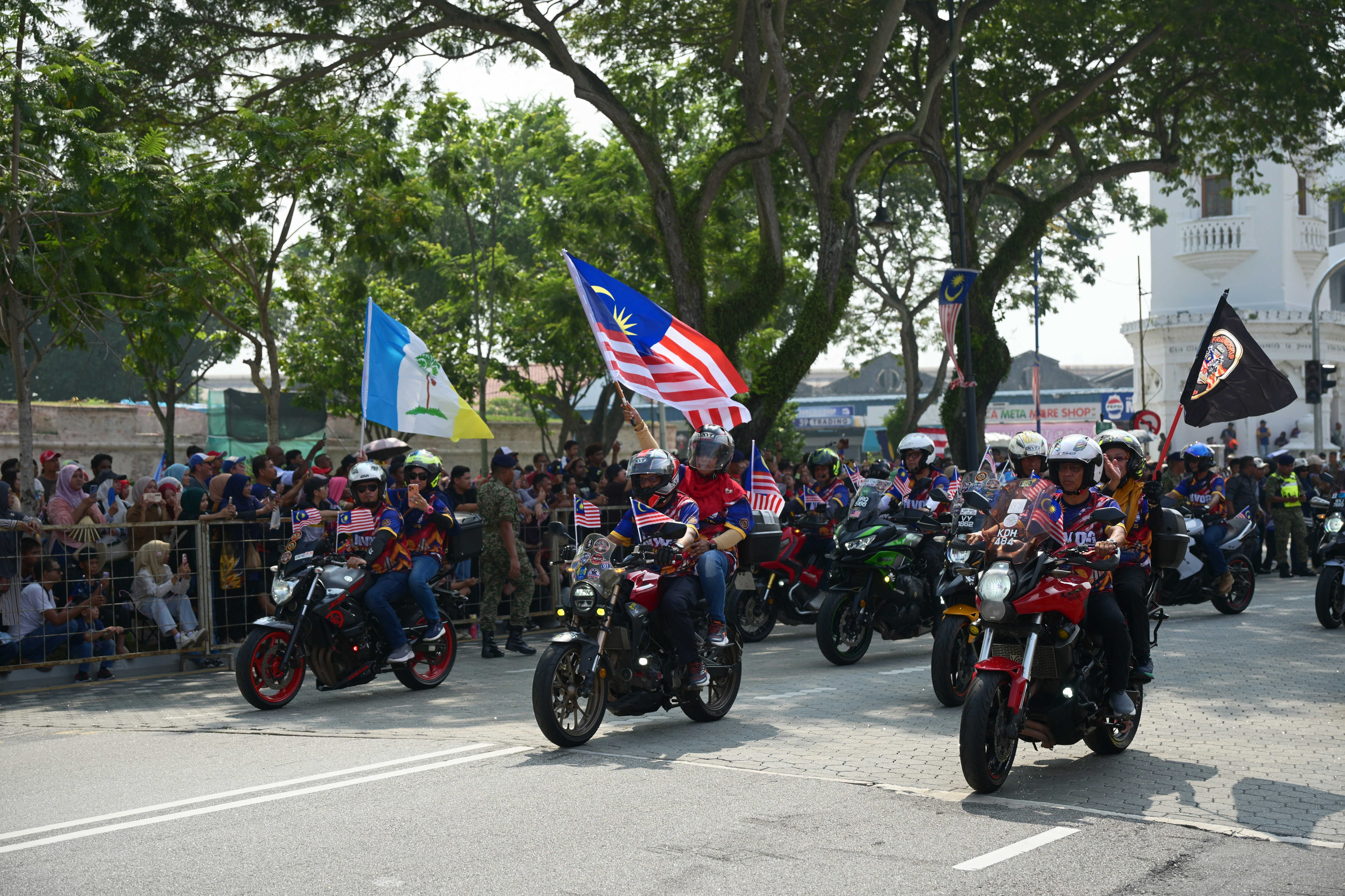 Flag-waving Parade of Motorbikes on a Sunlit Street