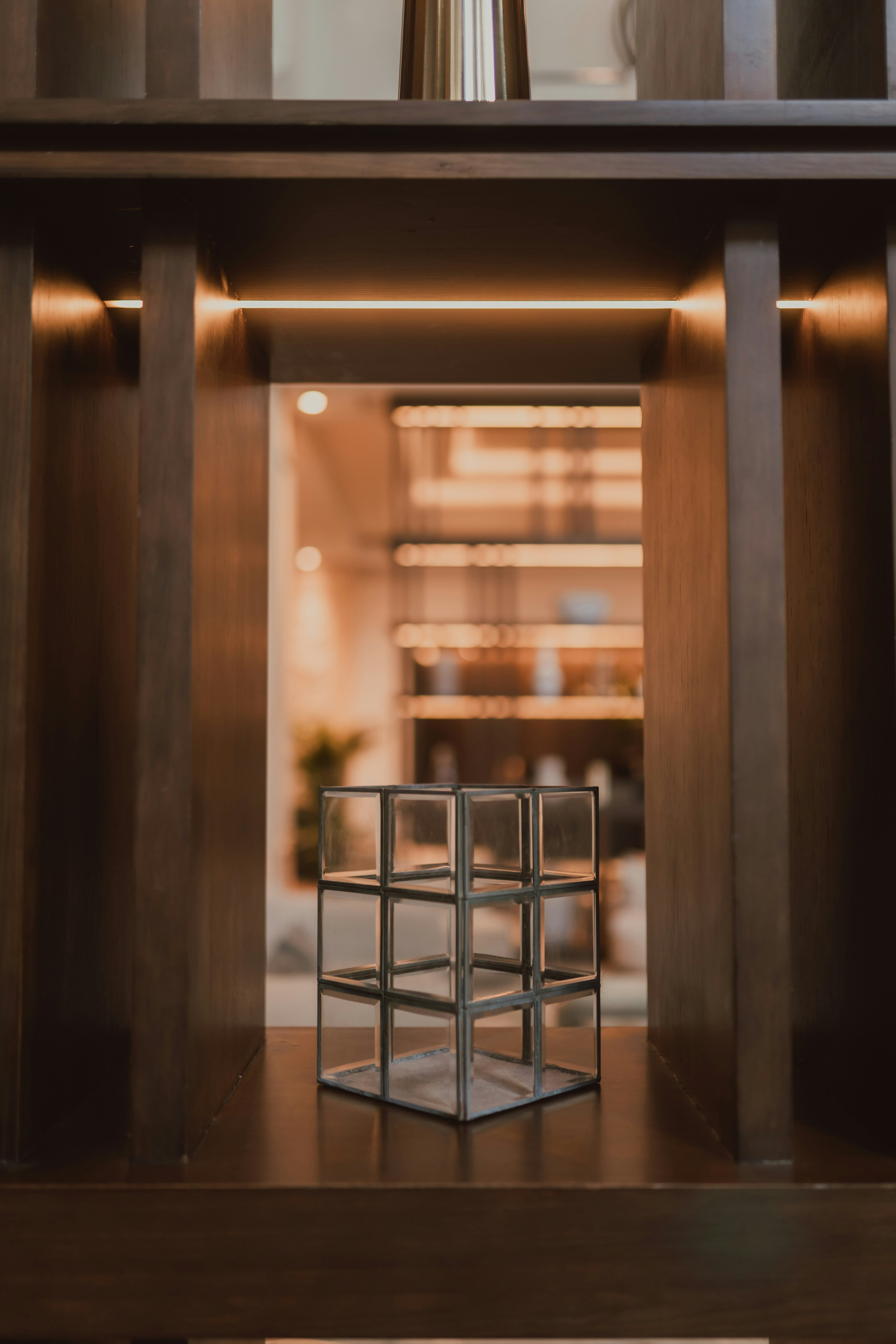 Geometric Glass Vessel on a Wooden Shelf Framed by Warm Architecture