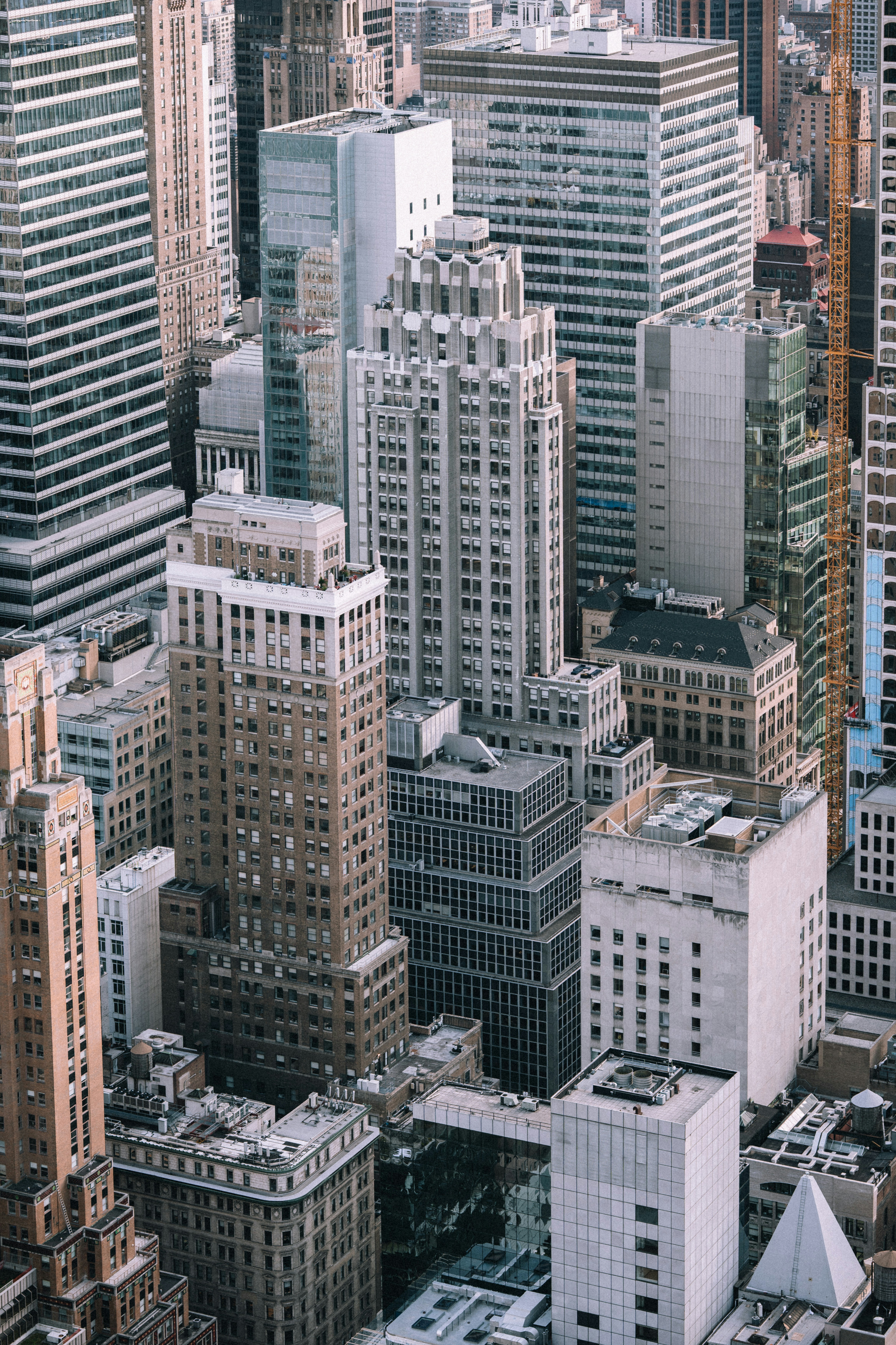 Dense cluster of modern high-rise buildings viewed from above, showcasing varied architectural styles and muted sunset tones.