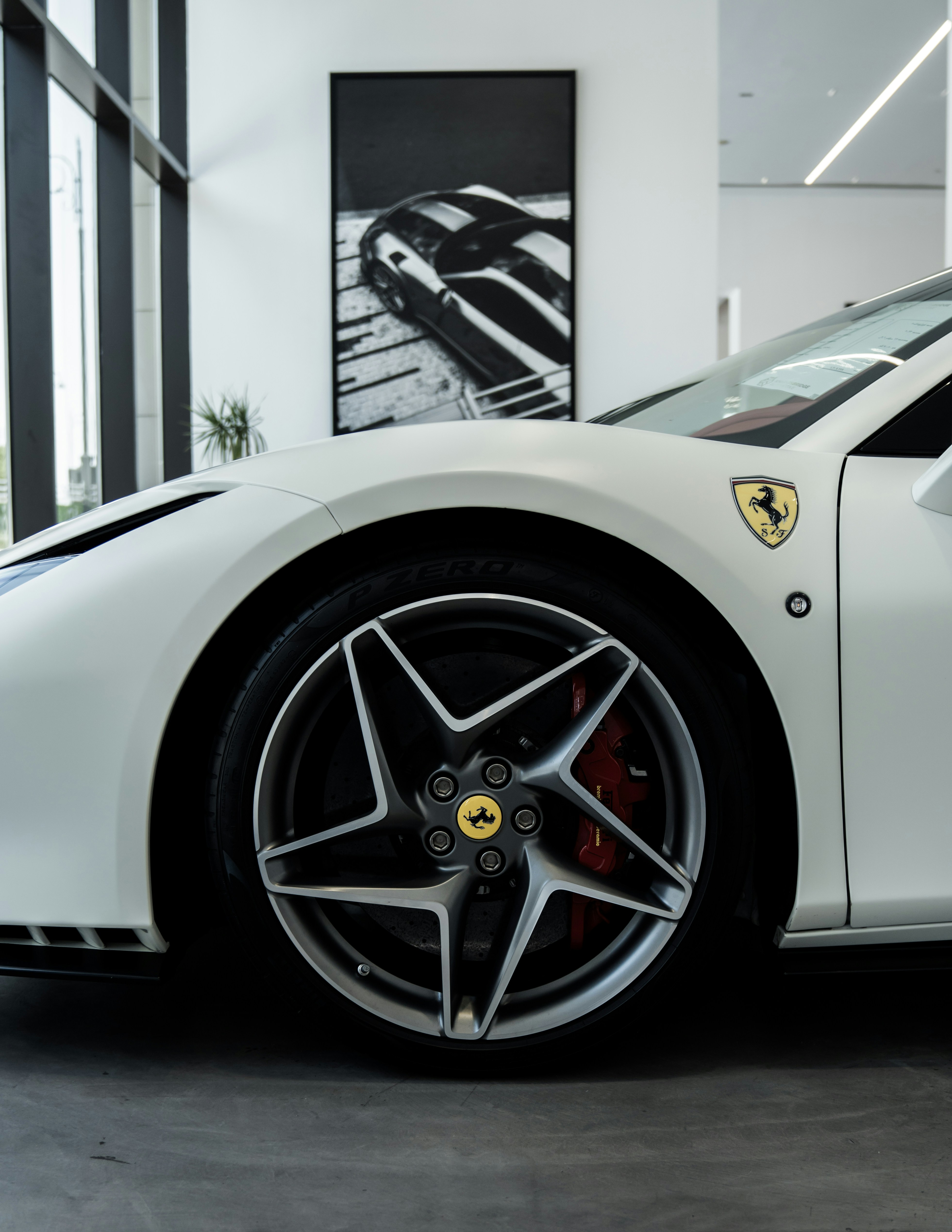 White Ferrari with Red Brake Calipers: Close-Up of the Front Wheel and Badge