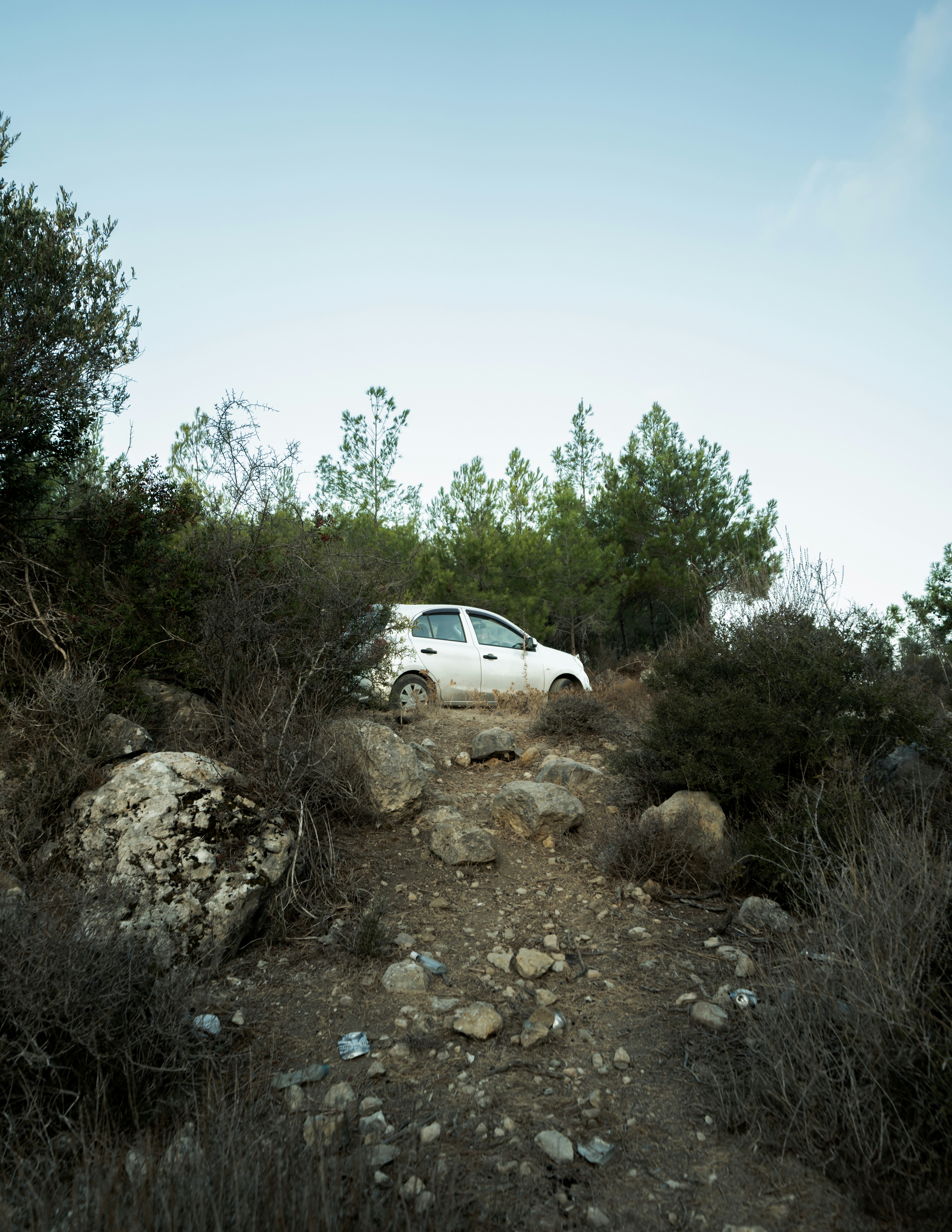 White SUV Resting Among Rough Terrain Beneath Open Sky