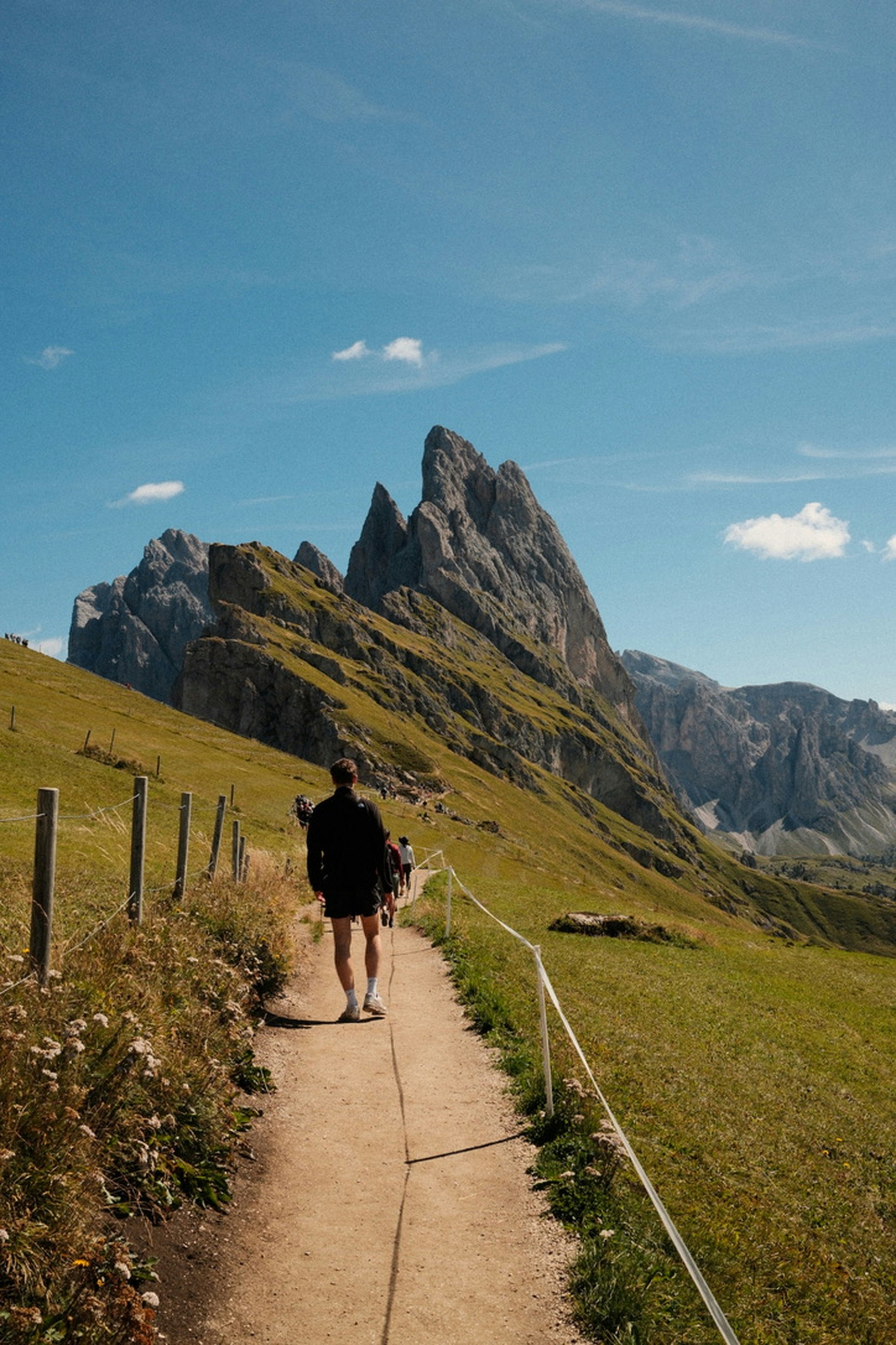 Trail to the jagged peak: hikers ascending under a clear alpine sky