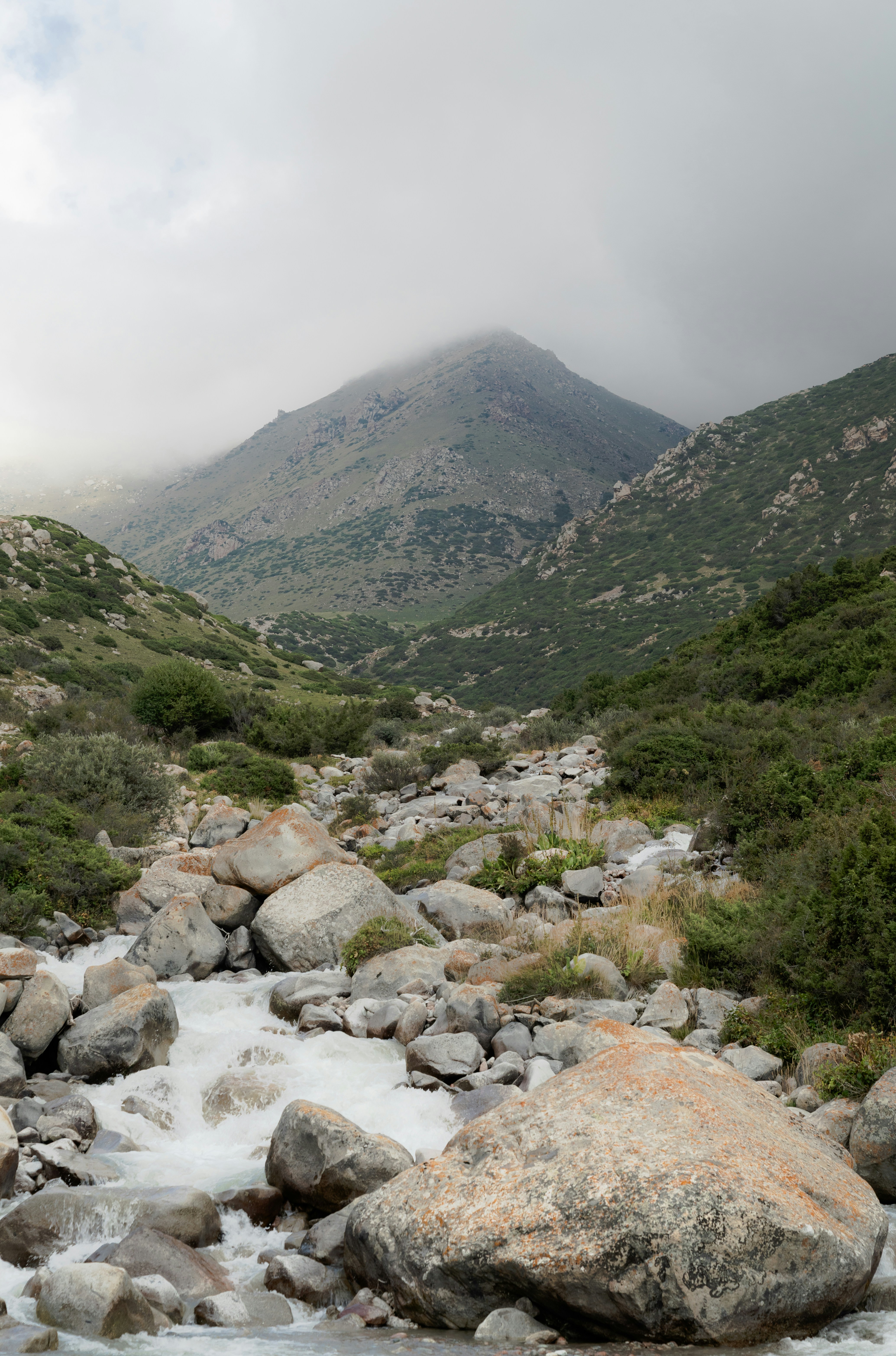 Rugged Riverbed Ascent Beneath Cloud-Wreathed Peak