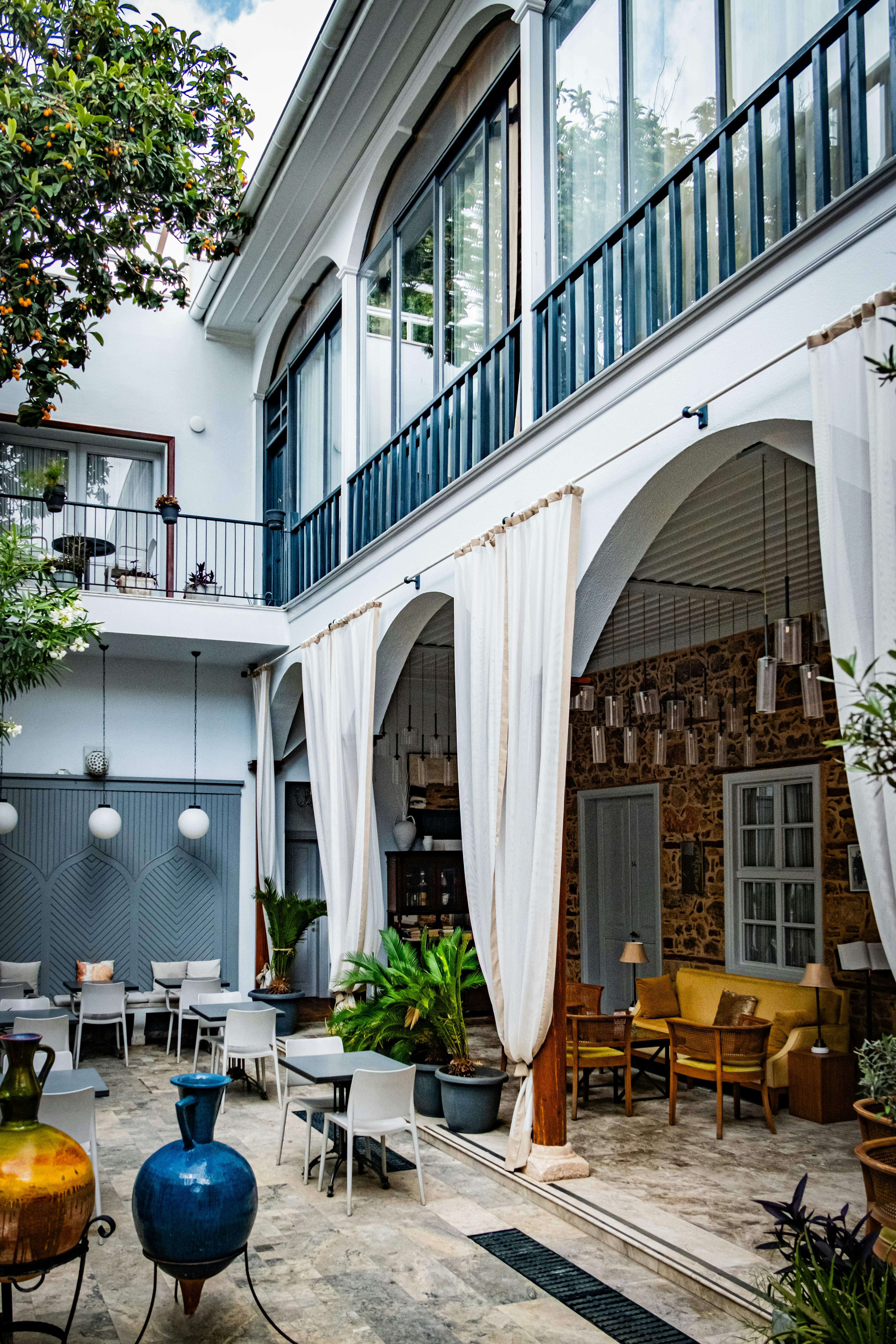 Courtyard Café Under Archways with White Drapes and Blue Accents