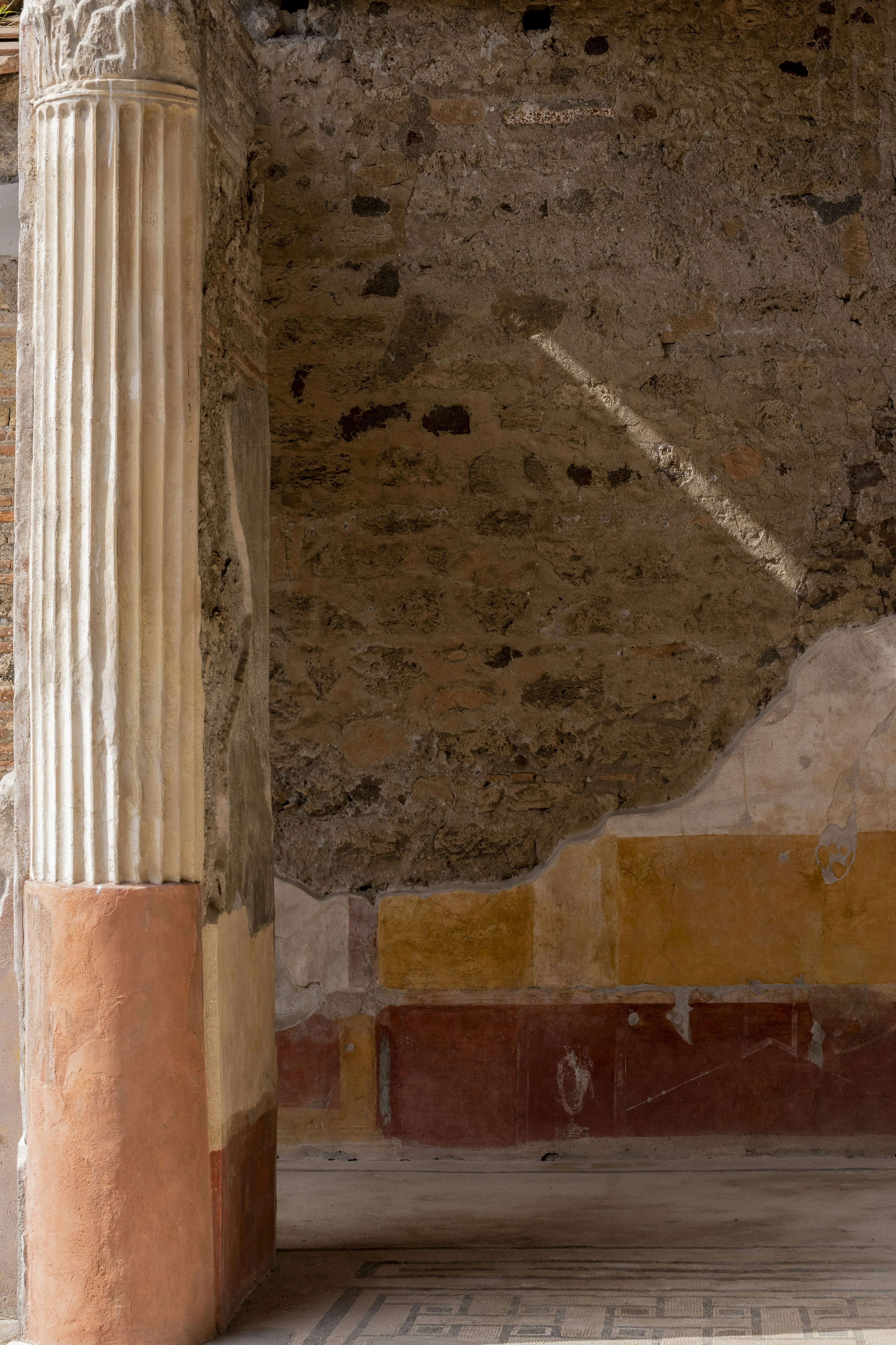 Ancient Column Framed by Weathered Wall in Dusk-lit Interior