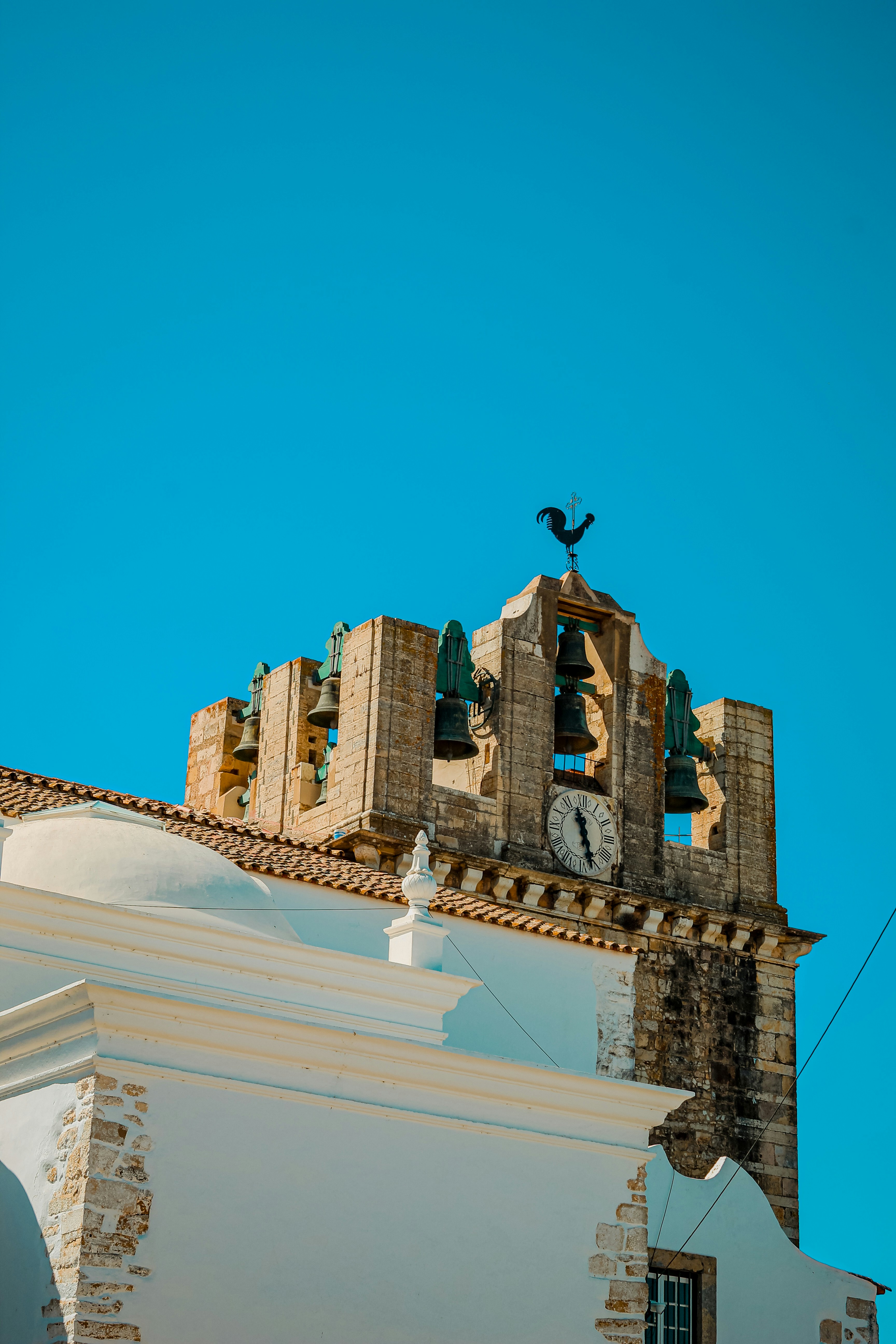 A Clocktower Crowned by a Rooster Weather Vane Against a Cerulean Sky