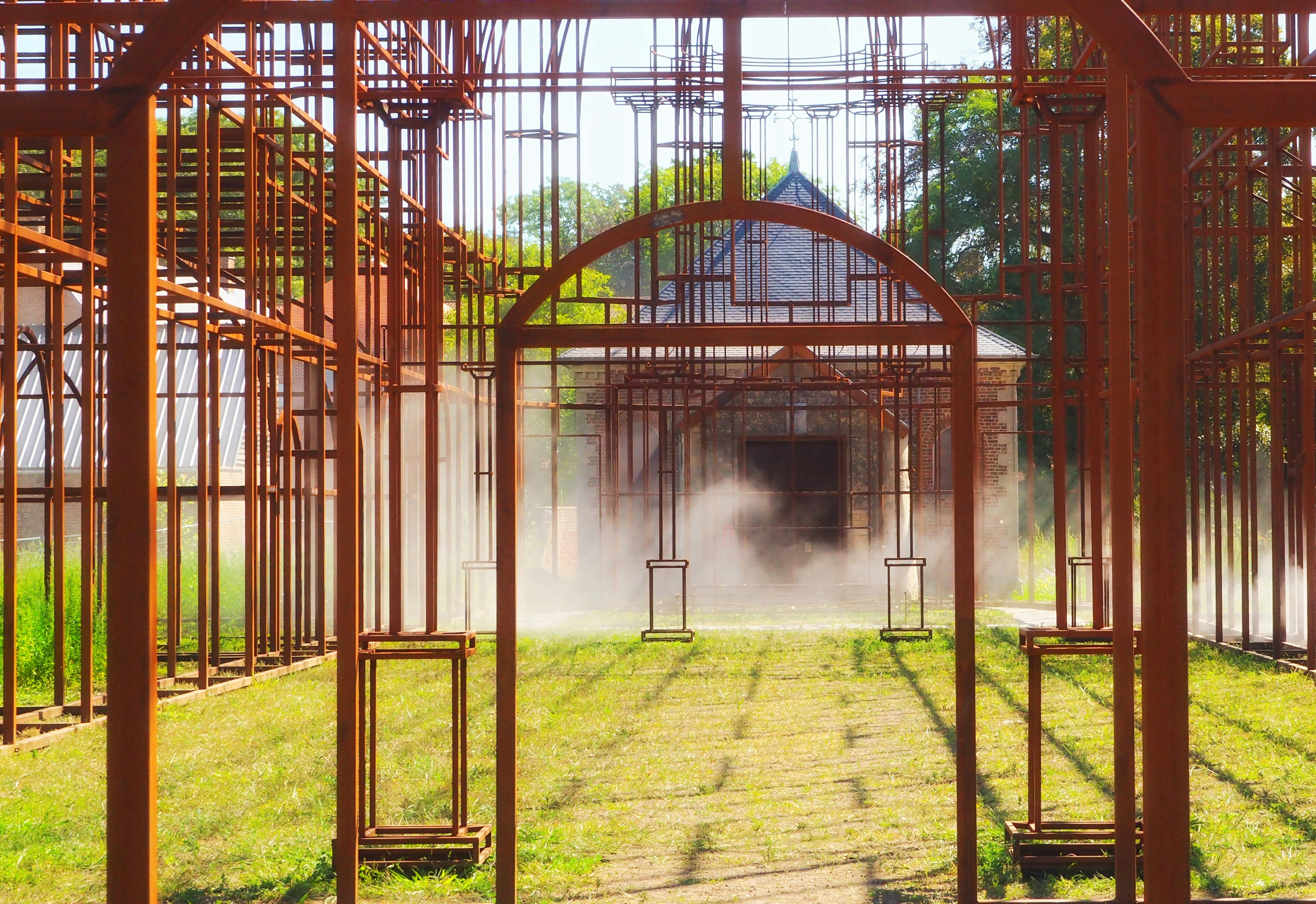 Rusted arches and drifting mist in an empty garden hall