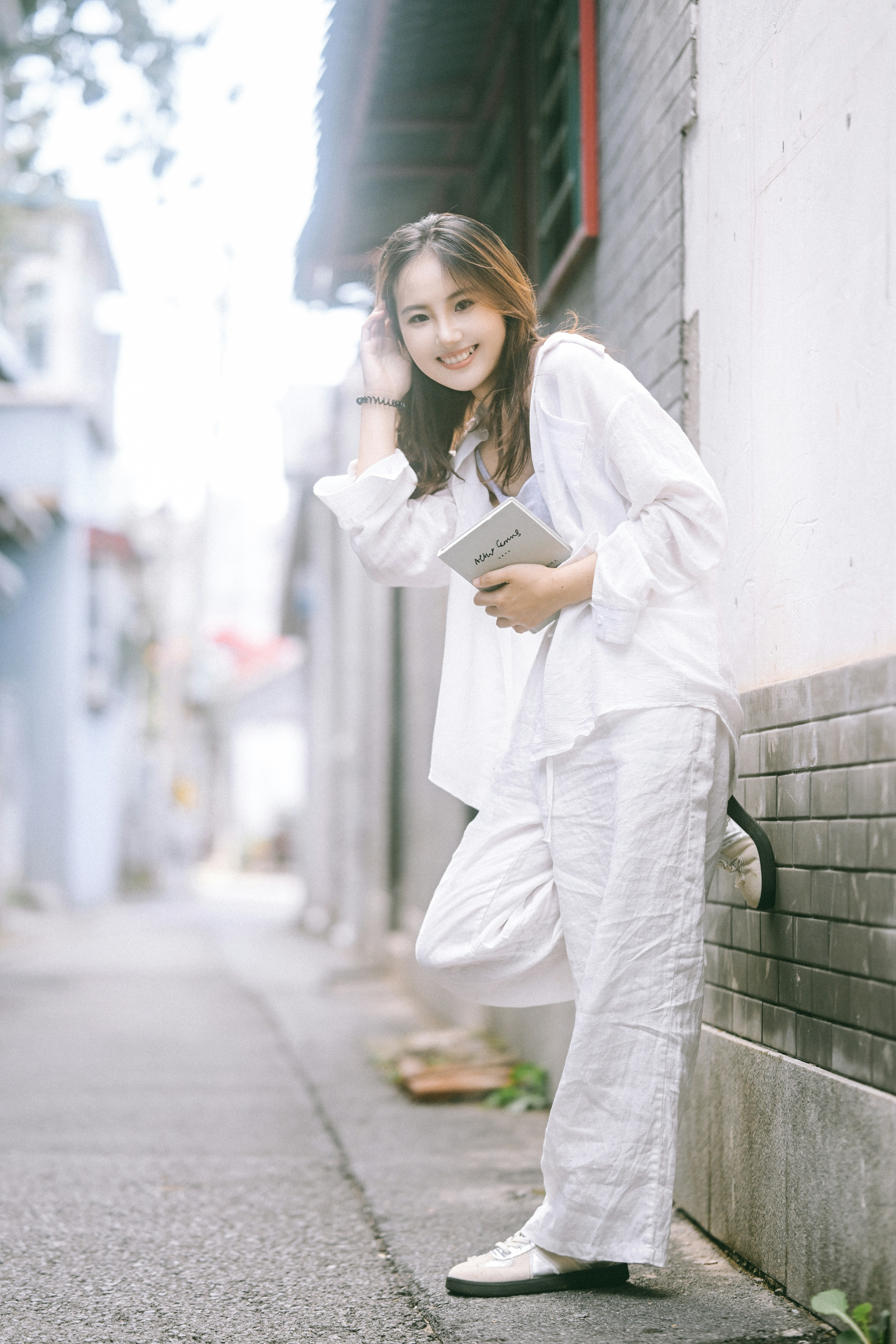 White-clad wanderer with a notebook in an urban alley